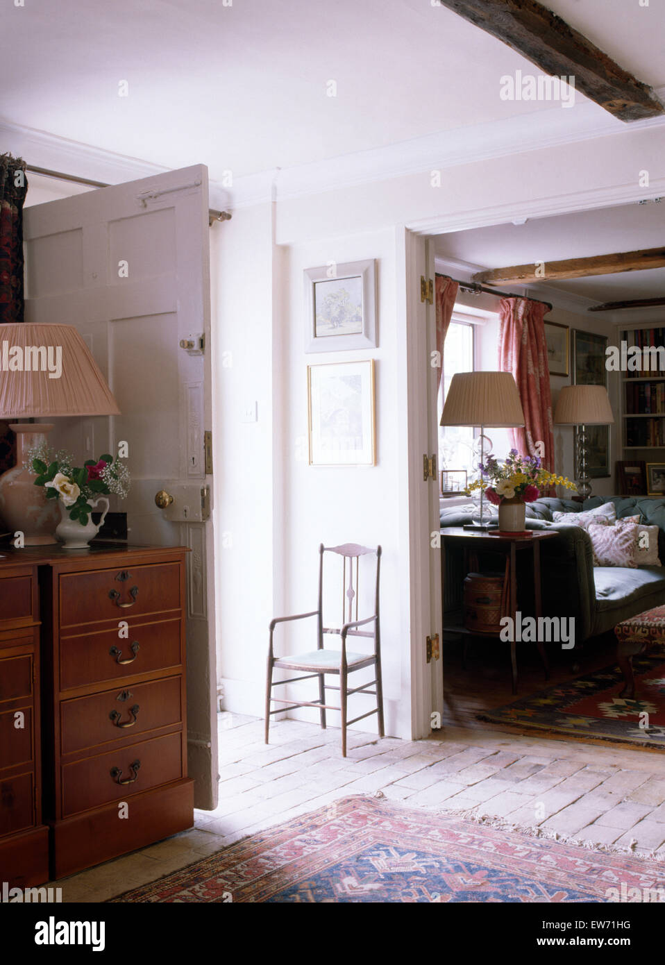 Door open to sitting room in cottage hall with oriental rug on old ...