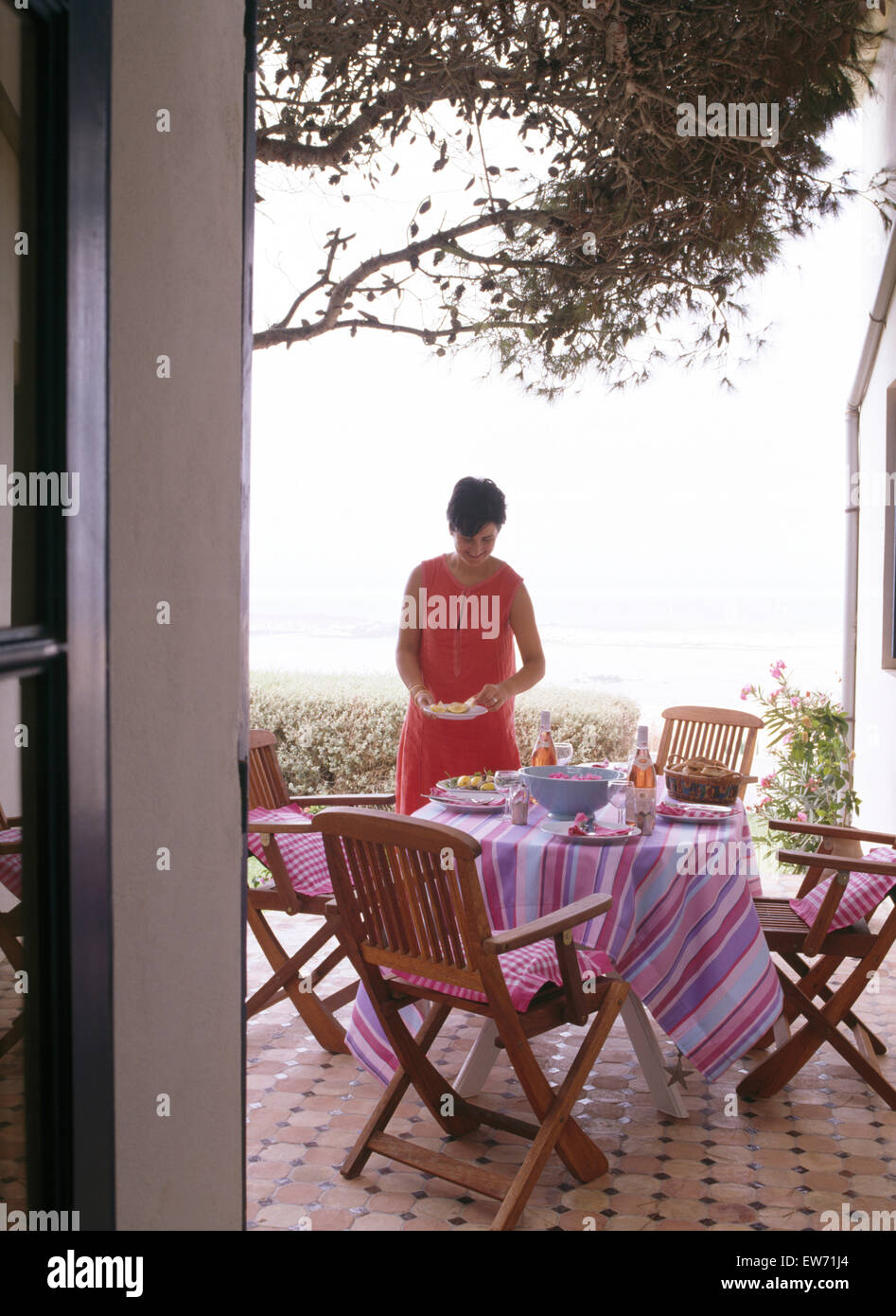 Woman setting table on terrace of villa on Corfu FOR EDITORIAL USE ONLY ...