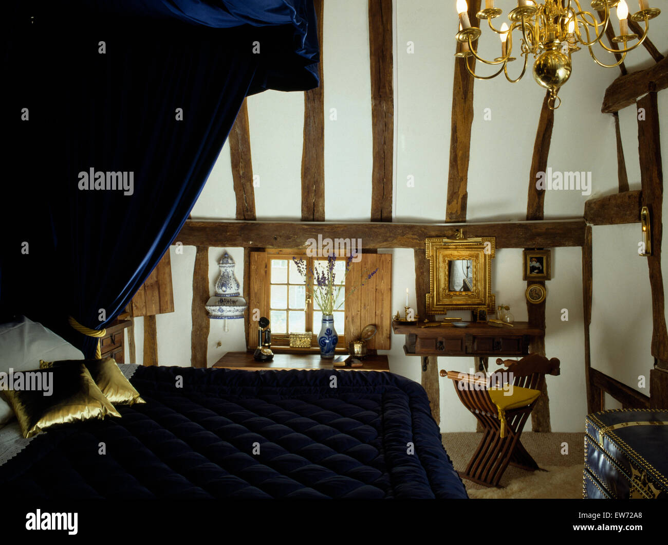 Blue velvet drapes and quilt on half tester bed with gold cushions in ...