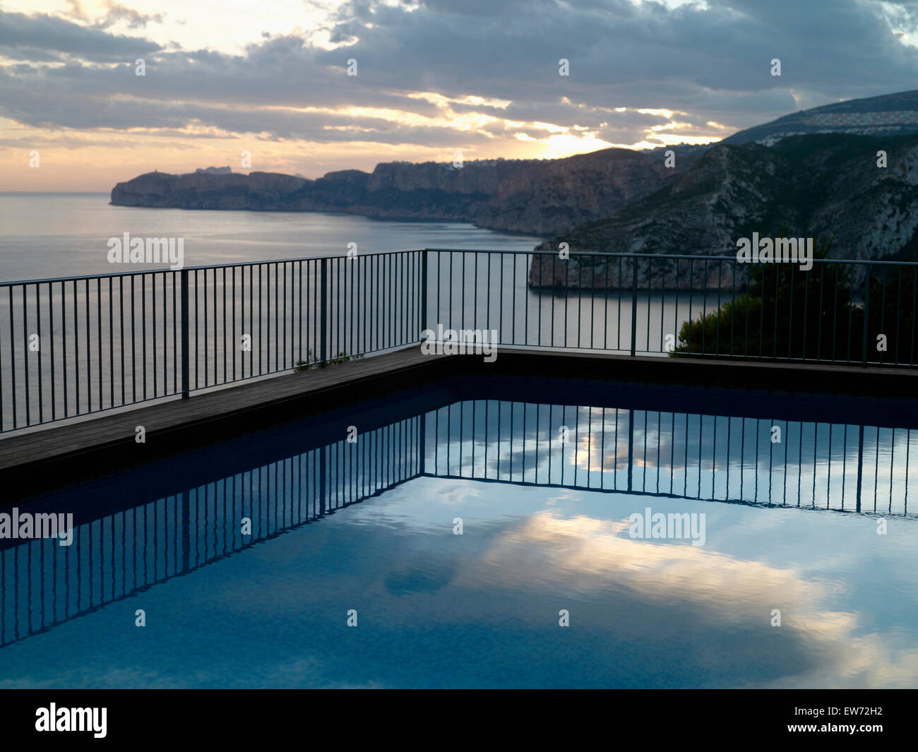 Clouds reflected in swimming pool overlooking the ocean in late evening ...