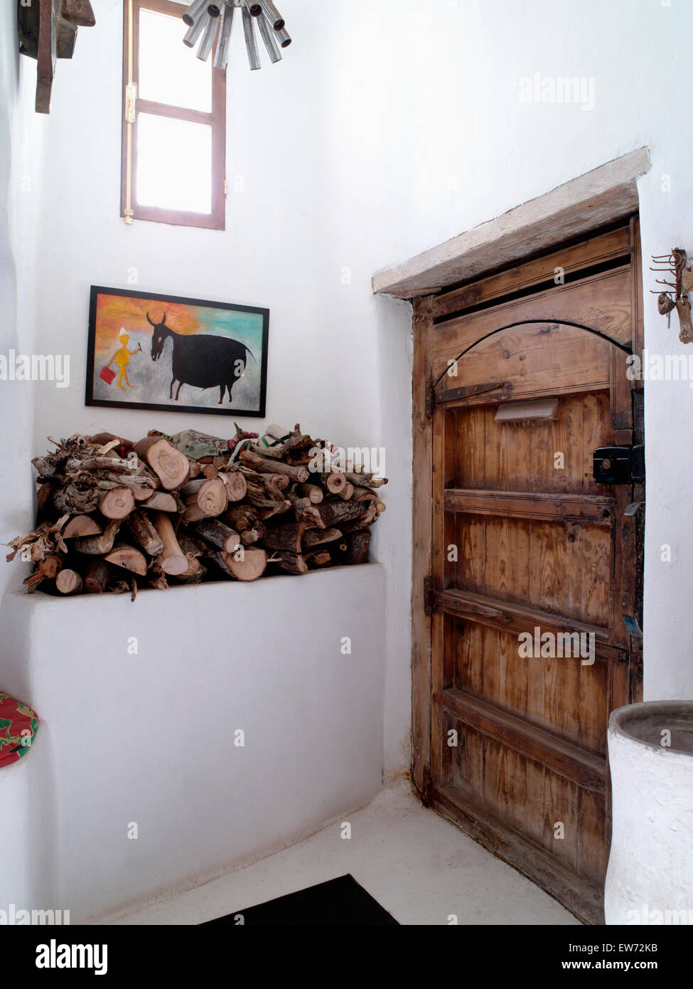 Logs stored on stone shelf beside rustic wooden door in modern white ...