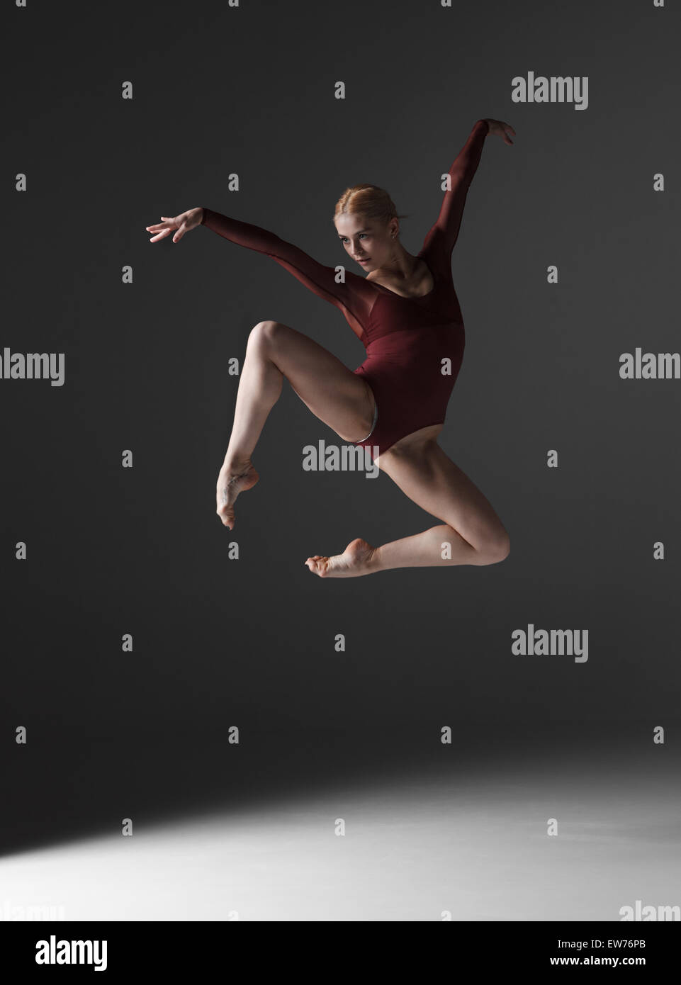 young beautiful modern style dancer jumping on a studio gray background ...