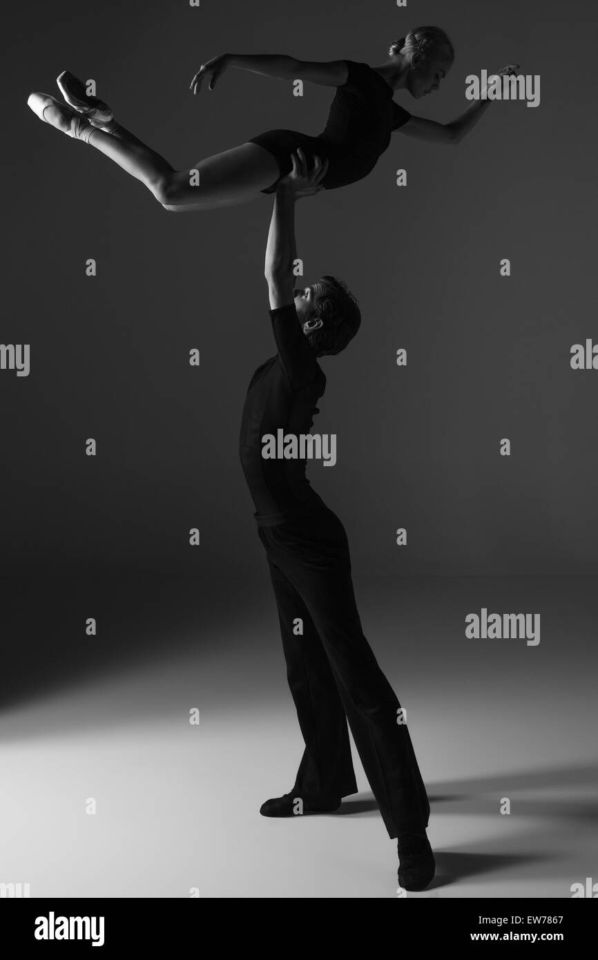 The two young modern ballet dancers in black suits posing over gray ...