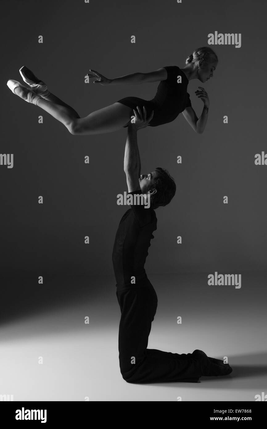 The two young modern ballet dancers in black suits posing over gray ...