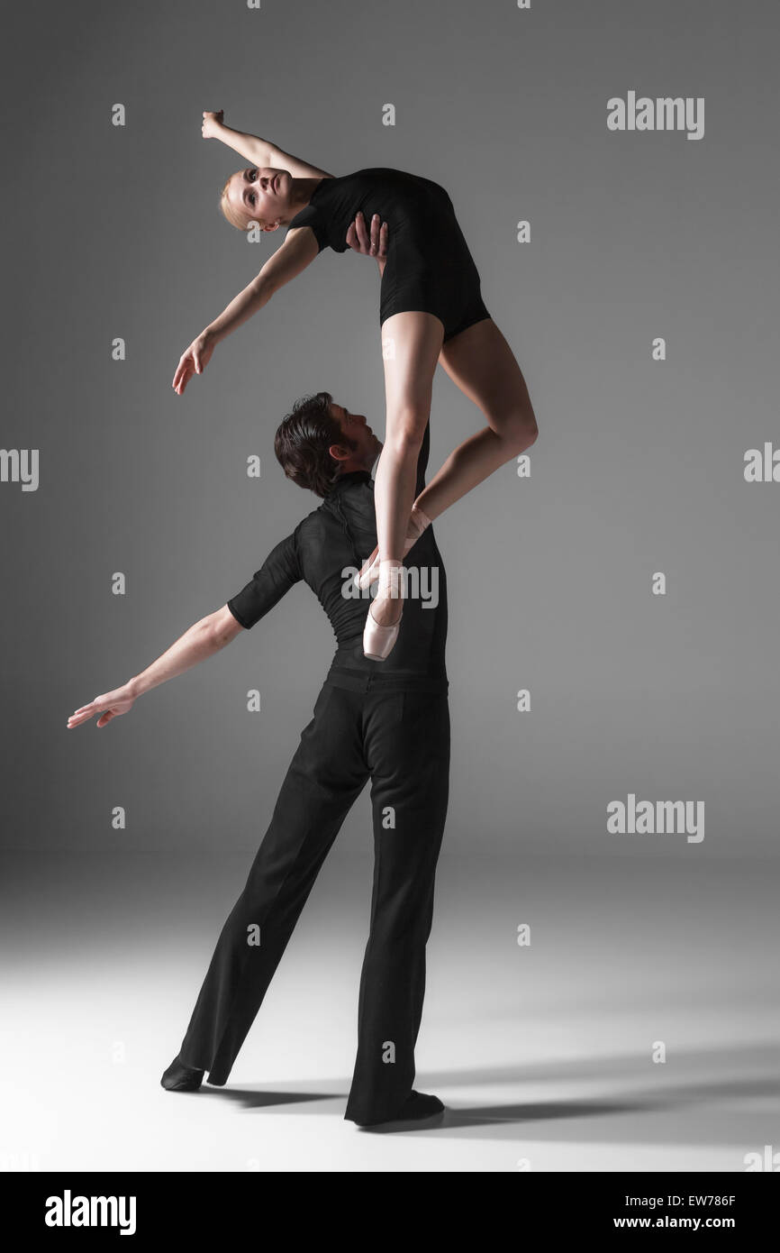 The two young modern ballet dancers in black suits posing over gray ...