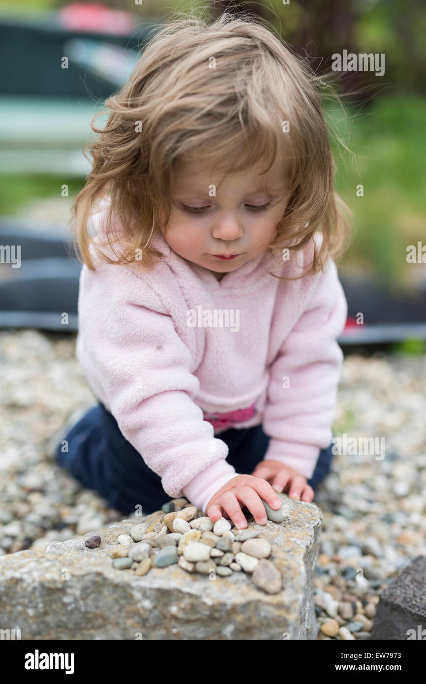 Little girl playing with pebbles Stock Photo - Alamy