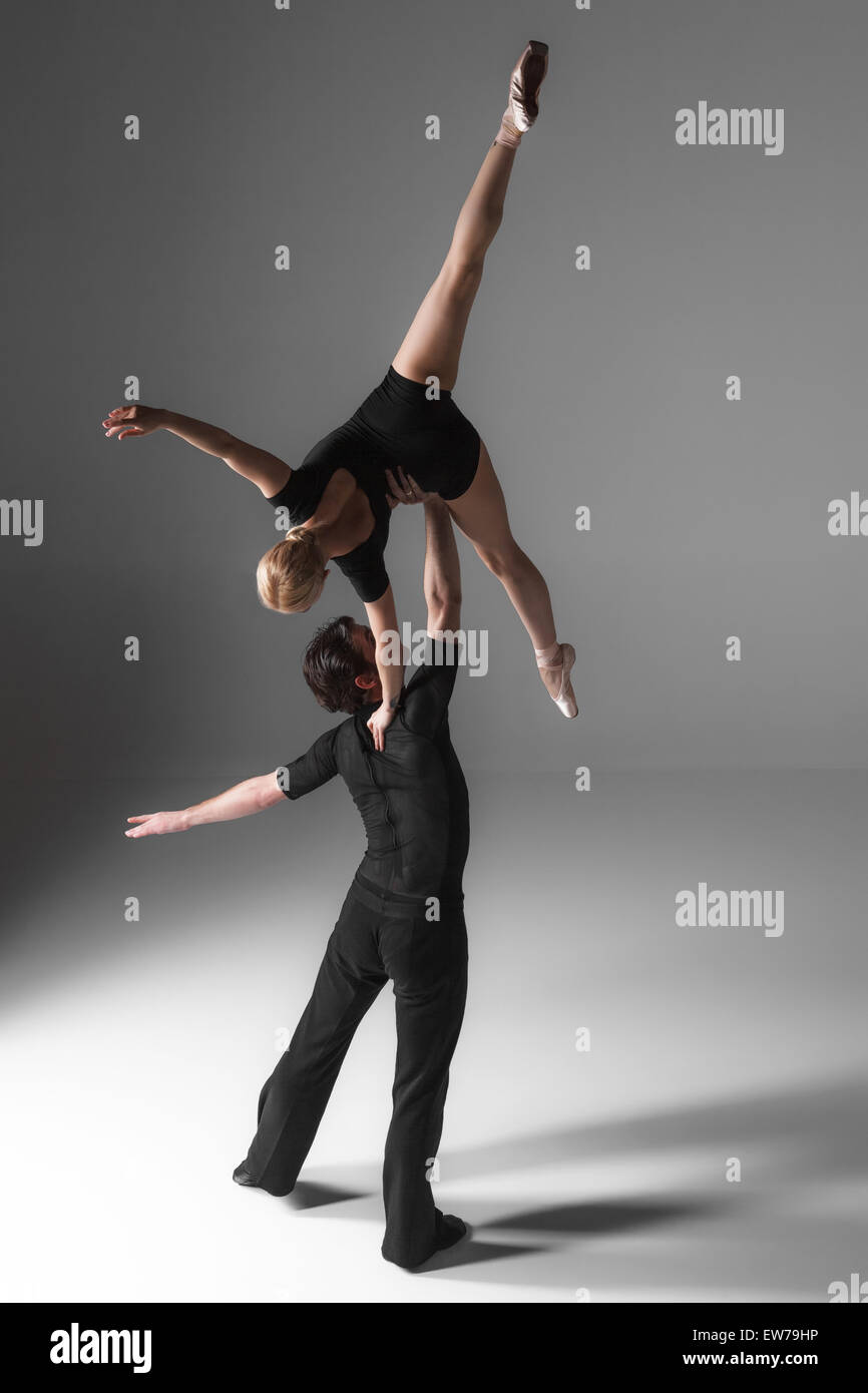 The two young modern ballet dancers in black suits posing over gray ...