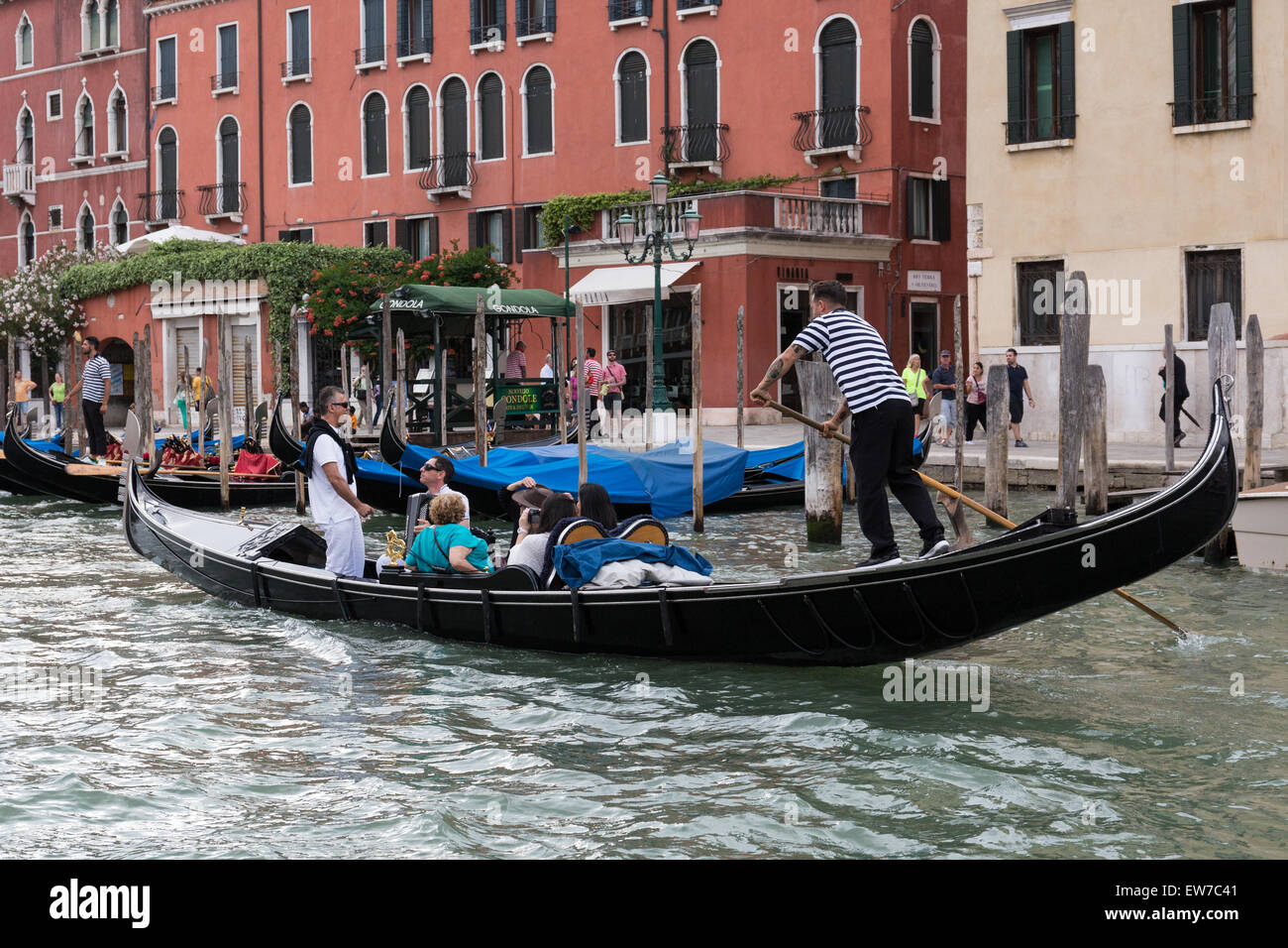 A man playing an accordian on a tourist gondola ride on the Grand Canal ...