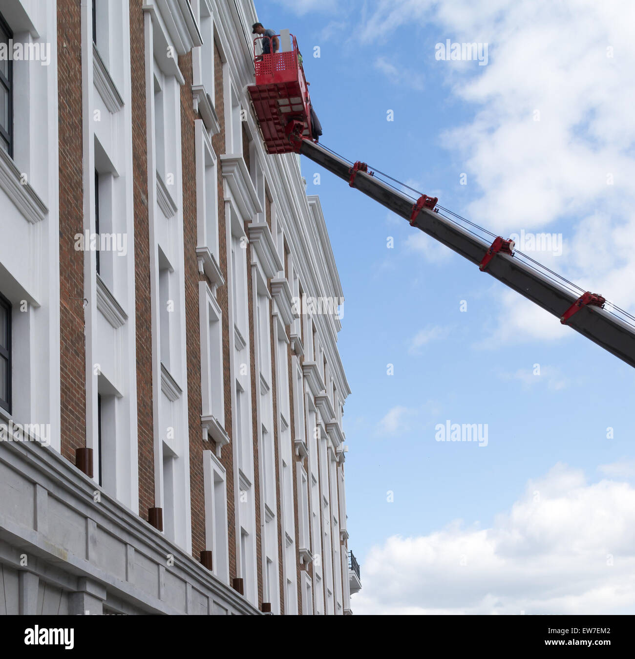 Workers working on a building facade using a red hydraulic lift Stock ...