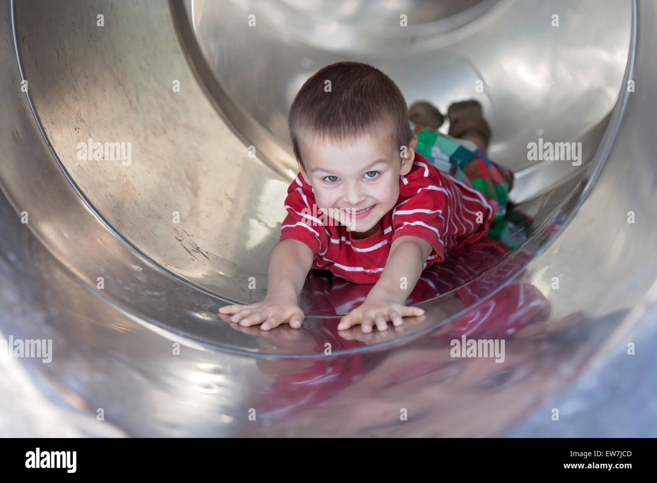Cute boy, sliding down the slide, smiling Stock Photo - Alamy