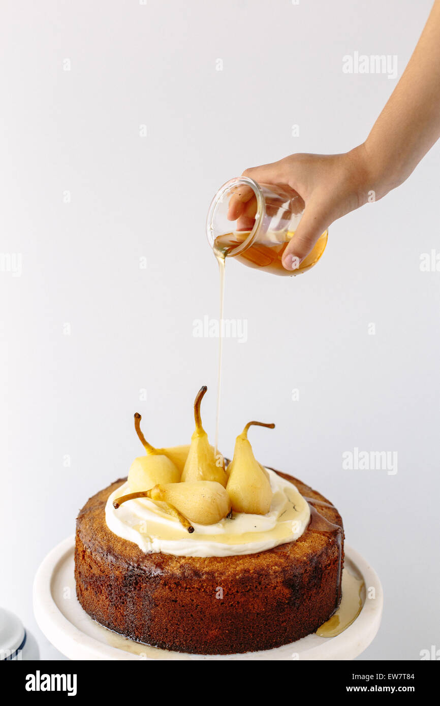 Honey being poured onto pear sponge cake Stock Photo - Alamy