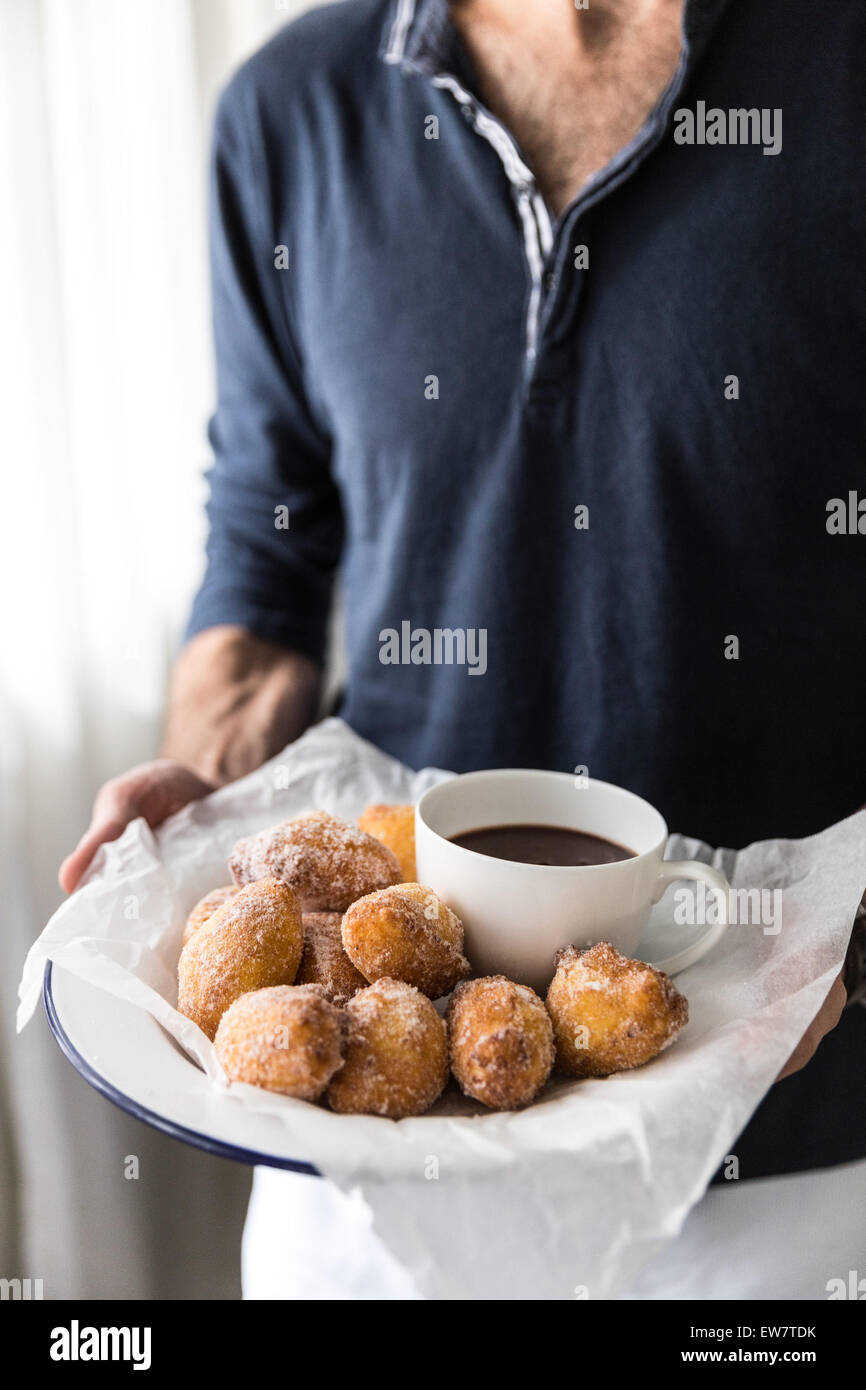 Man holding plate of donuts with a cup of chocolate sauce Stock Photo ...