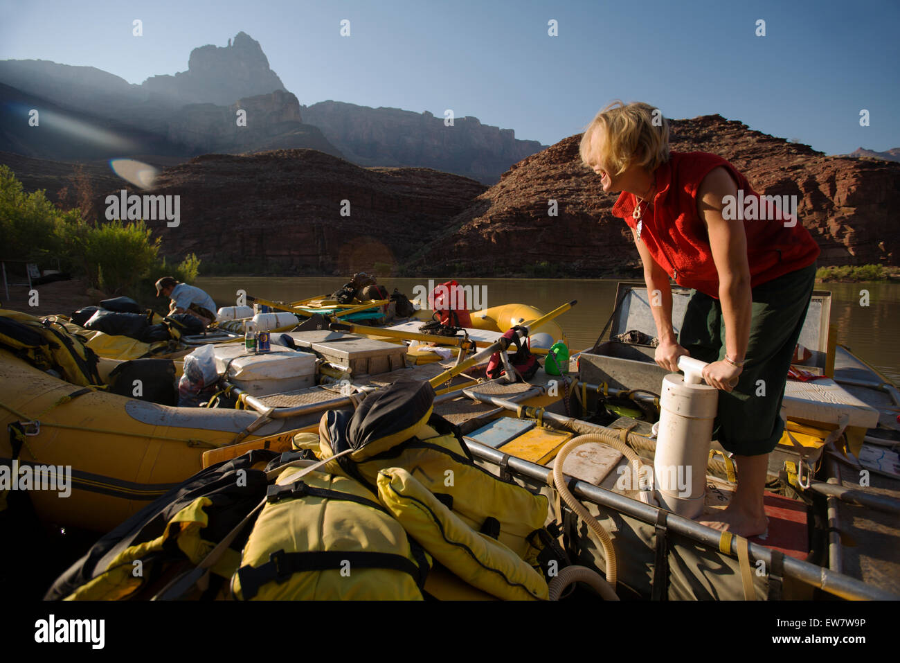 Woman inflating a raft by a river deep in a canyon Stock Photo - Alamy