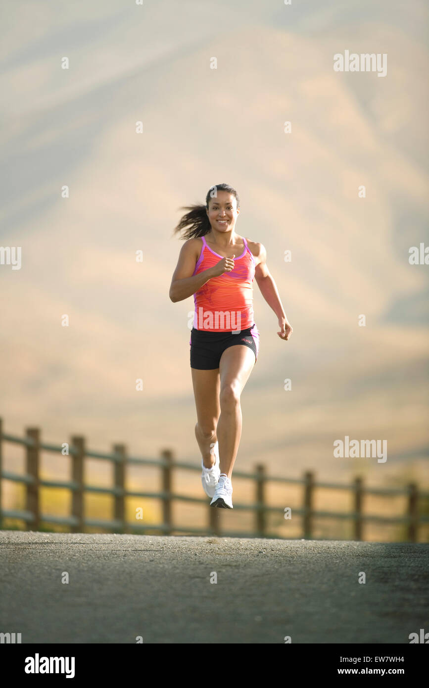 Attractive female runner running next to a fence Stock Photo - Alamy