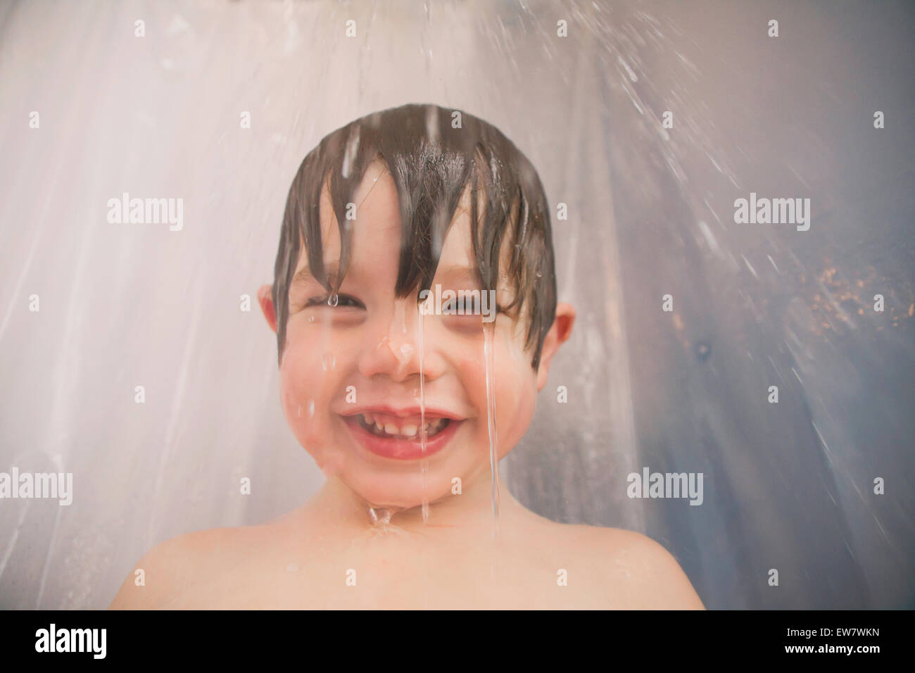 Smiling boy standing under a shower Stock Photo - Alamy