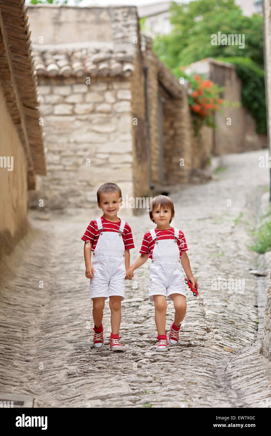 Two adorable kids, walking on the street, smiling at camera and holding ...