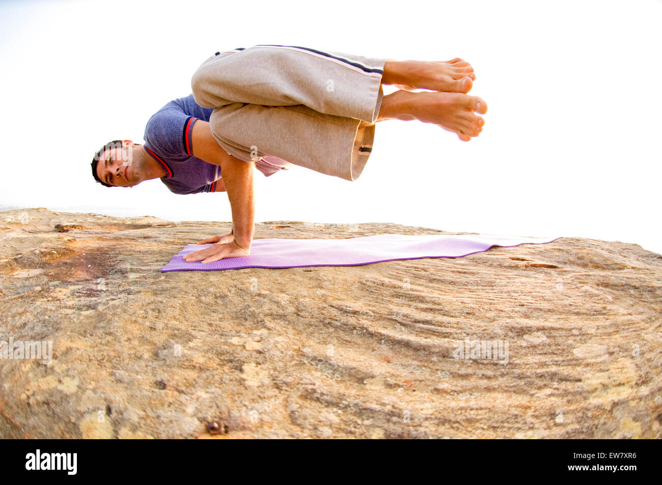 James Fellows practicing yoga on a rocky outcrop above the Pacific ...