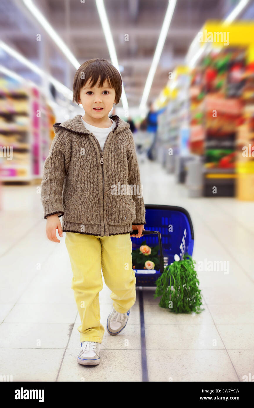 Adorable cute little and proud boy helping with grocery shopping ...