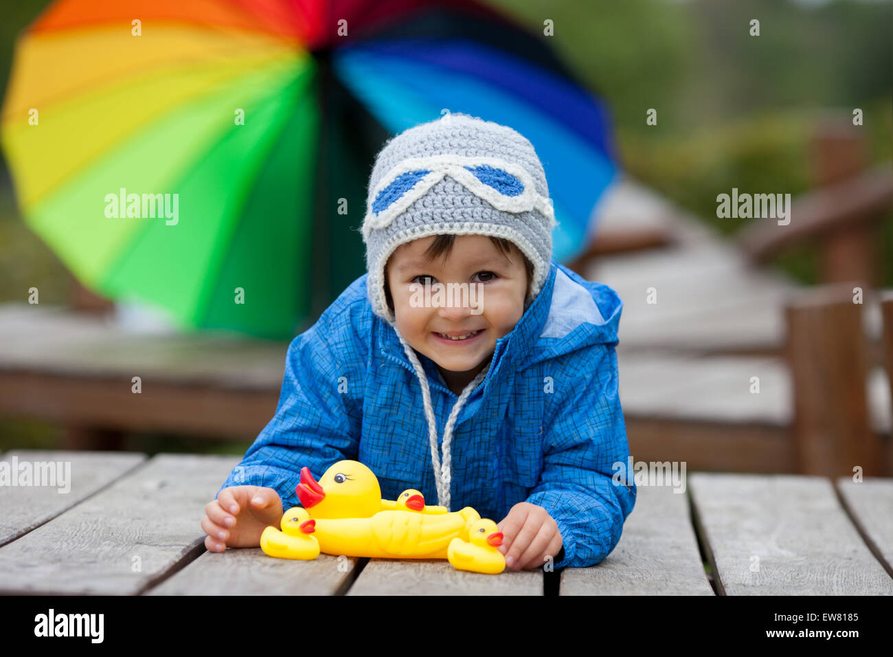 Adorable little boy, playing with rubber ducks outside on an autumn day ...