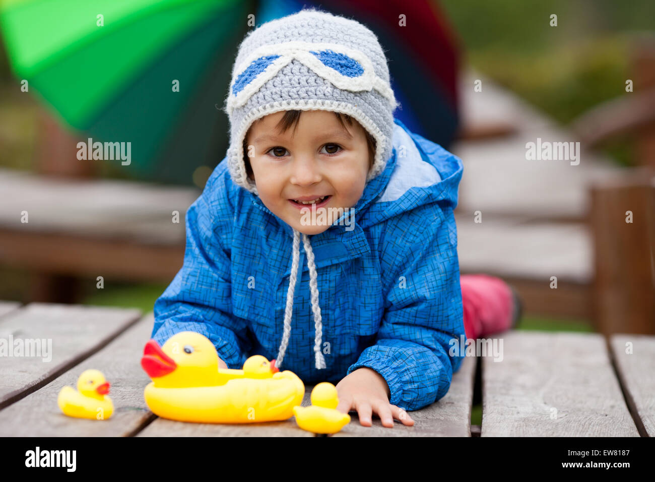 Adorable little boy, playing with rubber ducks outside on an autumn day ...