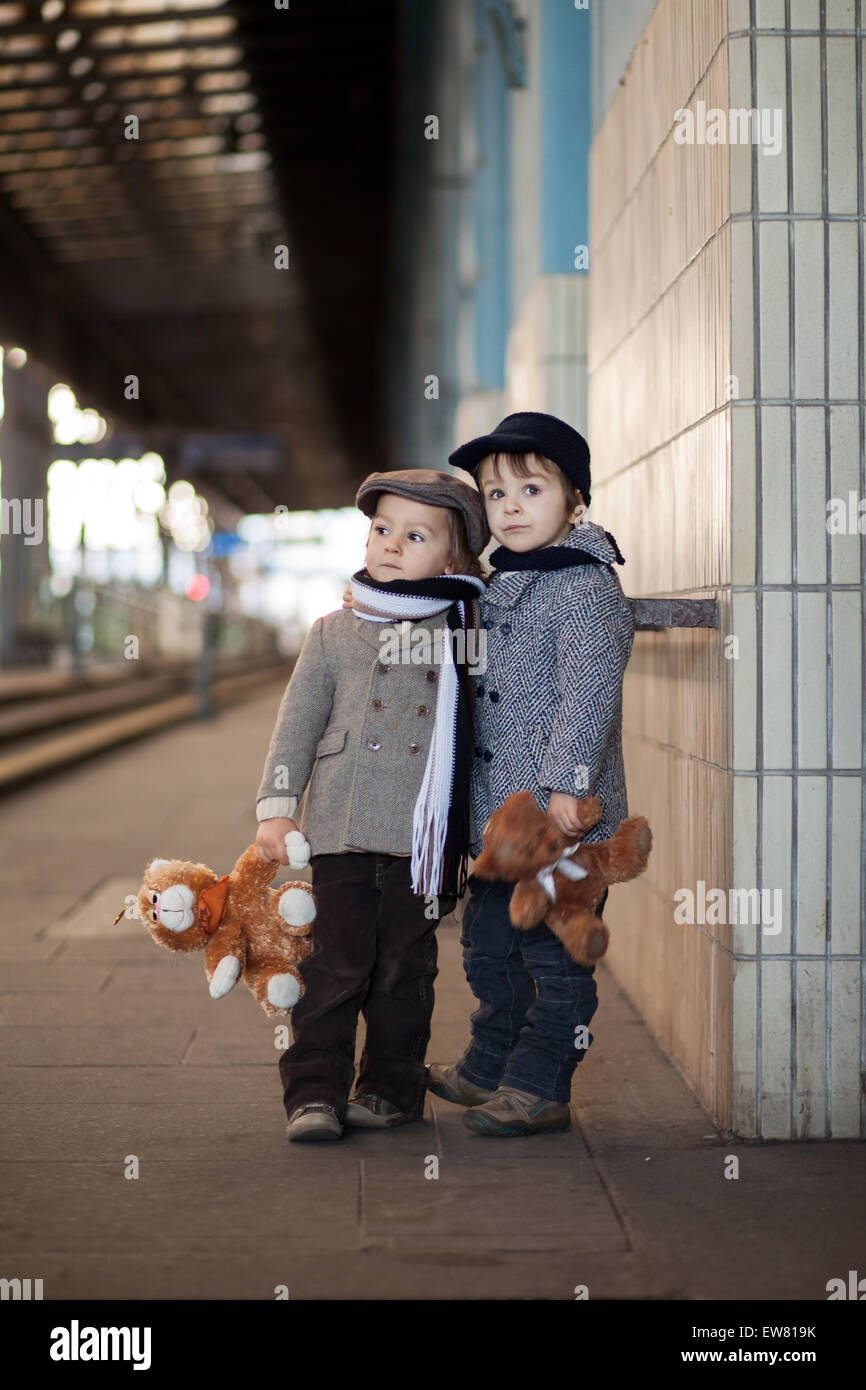 Two little boys with their teddy bears on the mail railway station in ...