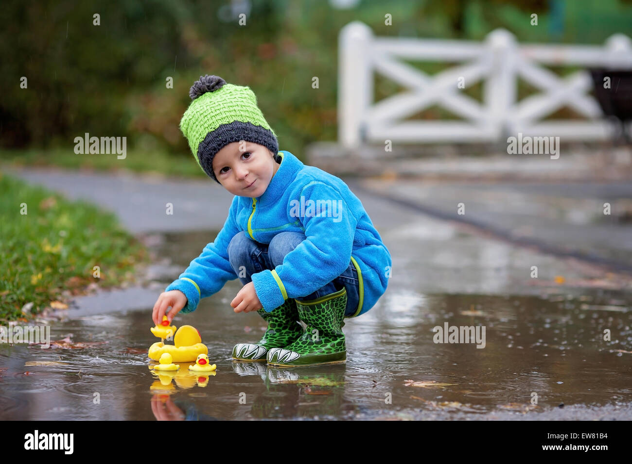 Little boy, jumping in muddy puddles in the park, rubber ducks in the ...