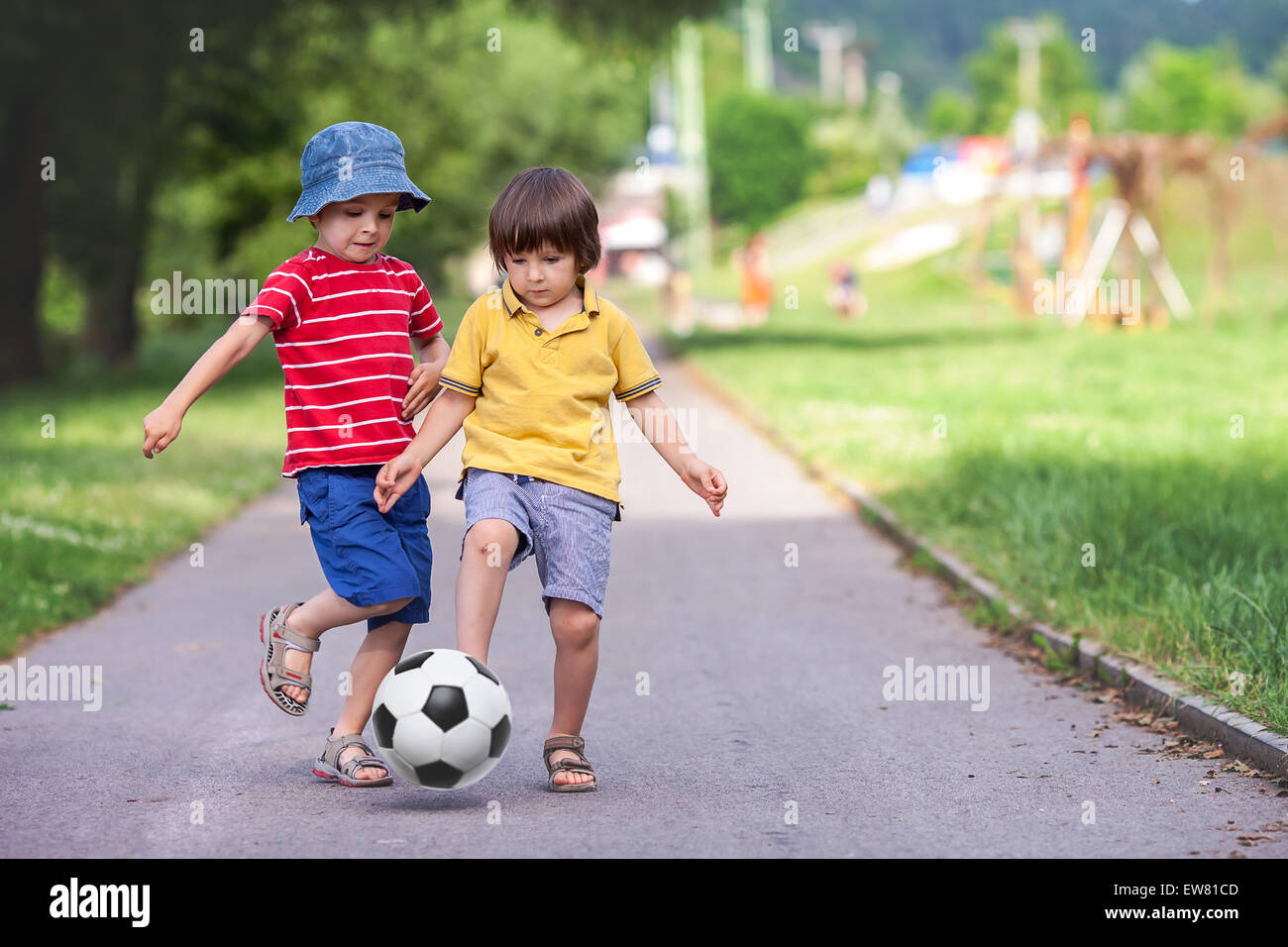 Two cute little kids, playing football together, summertime. Children ...