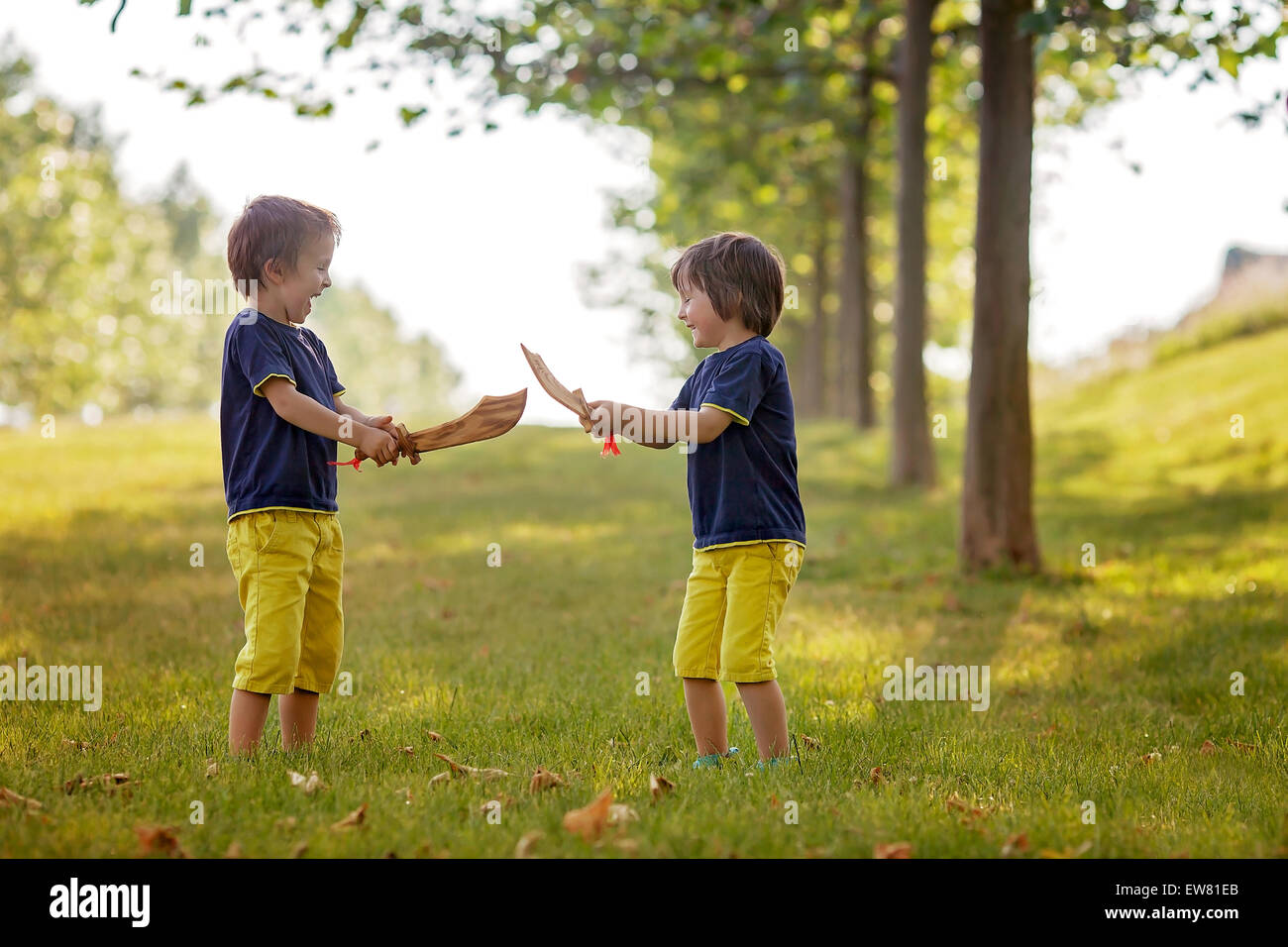 Two little boys, holding swords, glaring with a mad face at each other ...