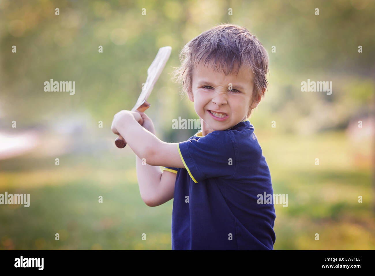 Angry little boy, holding sword, glaring with a mad face at the camera ...