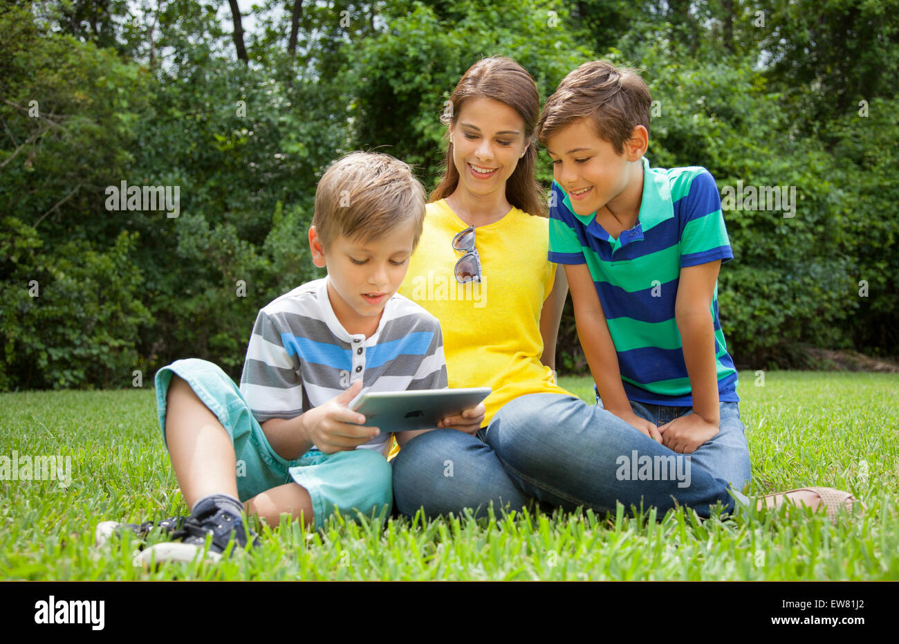 Young single mother with two boys playing on iPad tablet in yard Stock ...