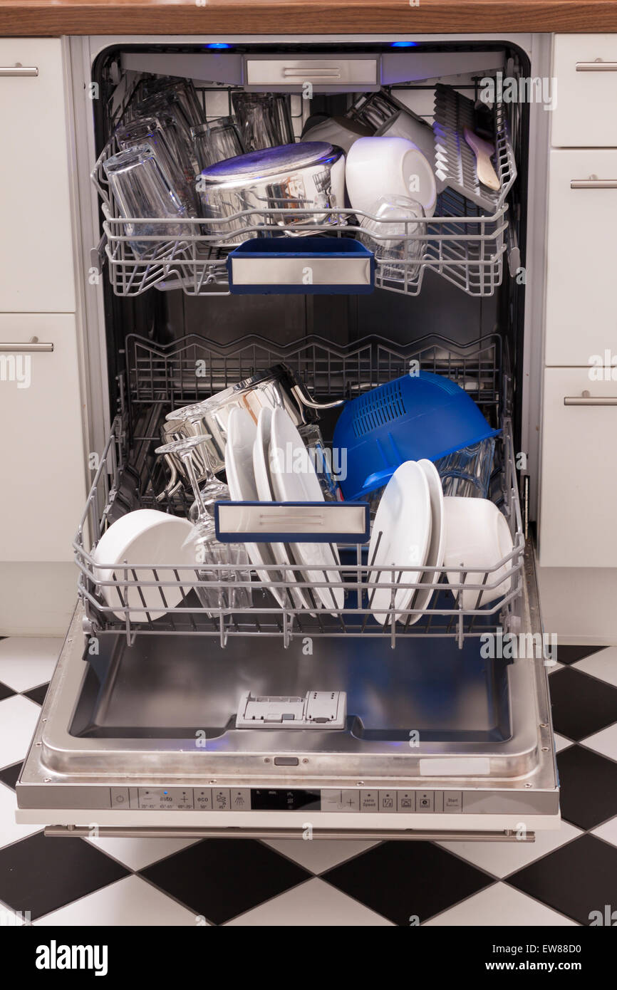 Dishwasher loades in a kitchen with clean dishes and blue light Stock ...