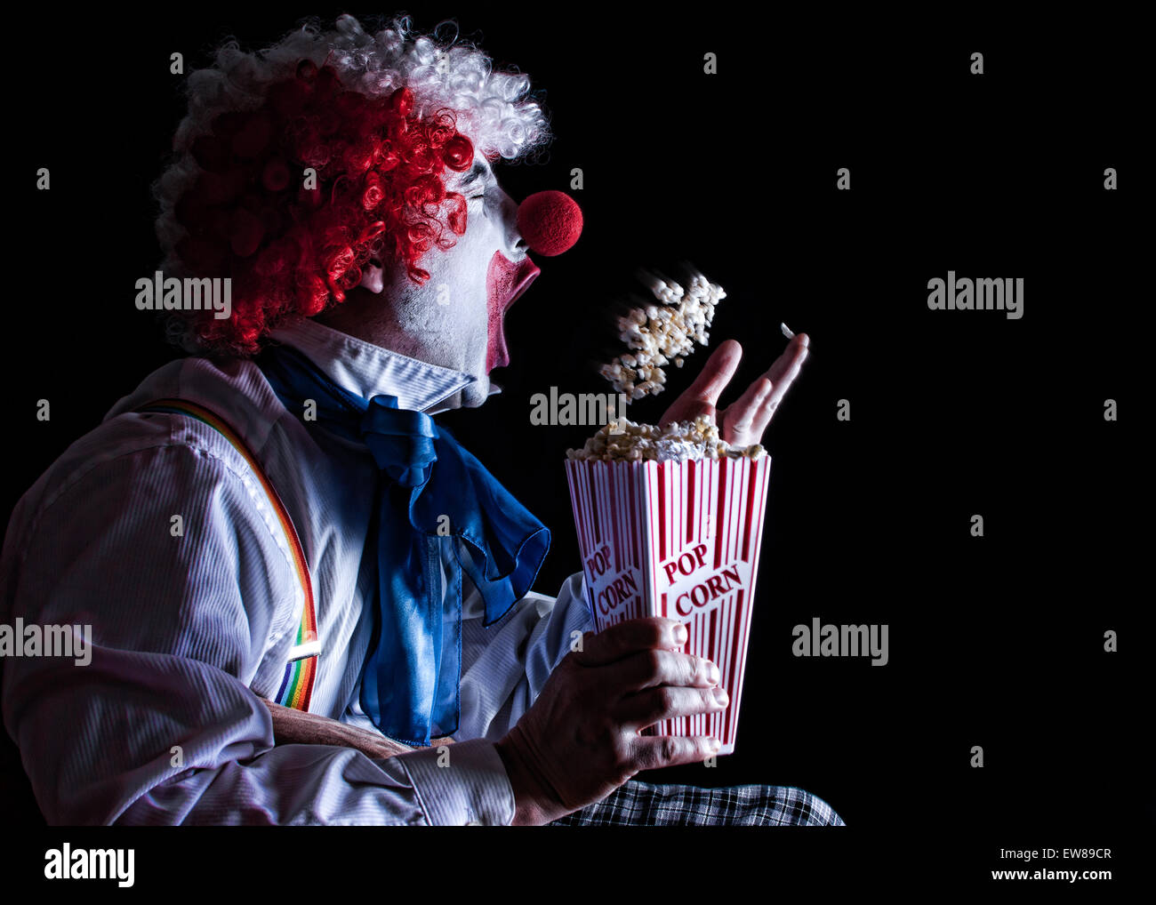 clown throwing popcorn into his mouth while watching a movie Stock ...