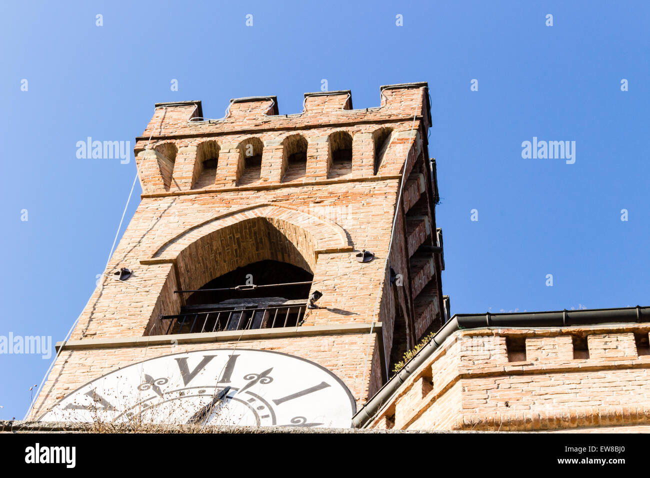 A medieval crenellated brick wall clock tower in a sunny winter day ...