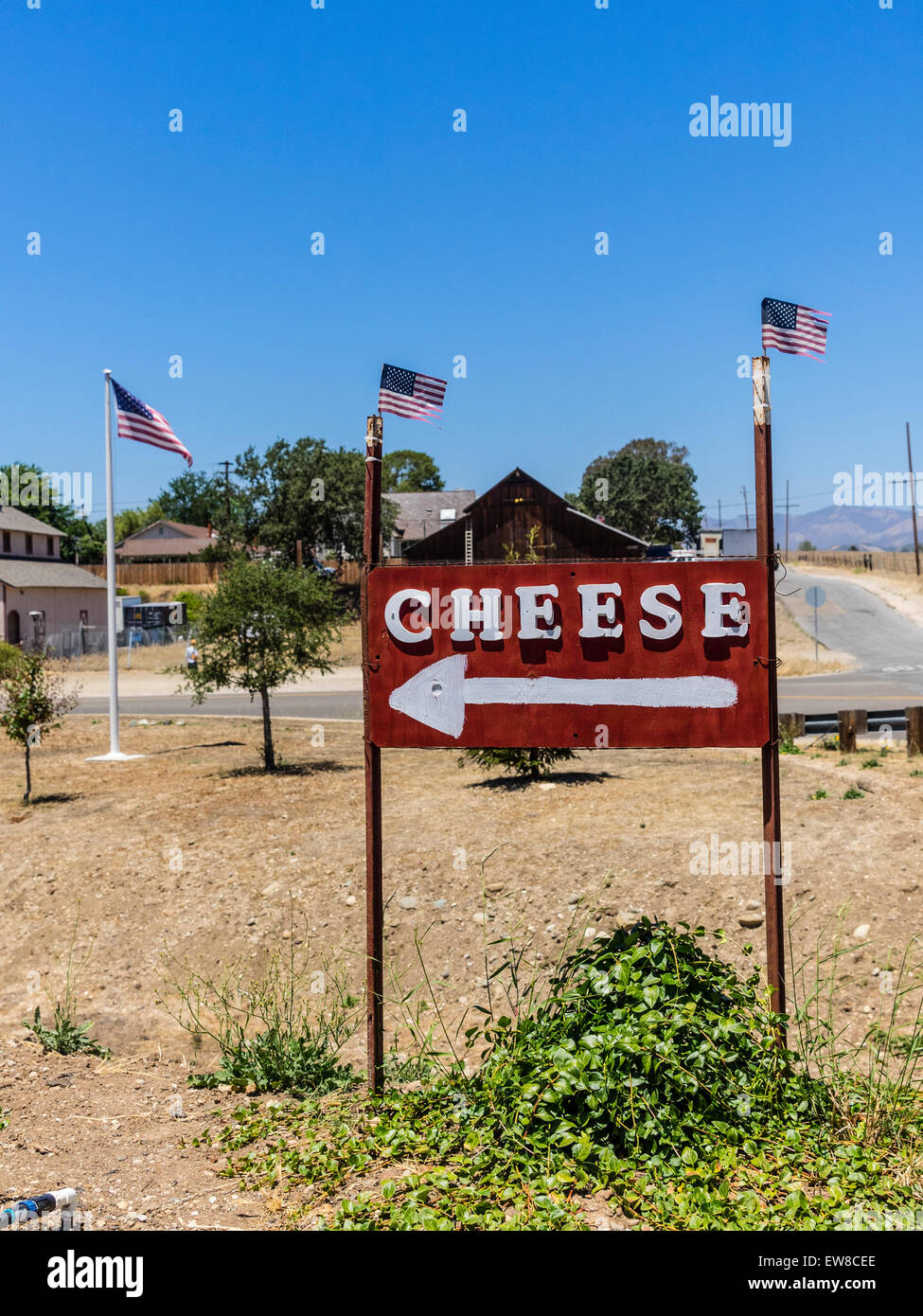A cheese sign is topped with two American Flags while another flies in ...