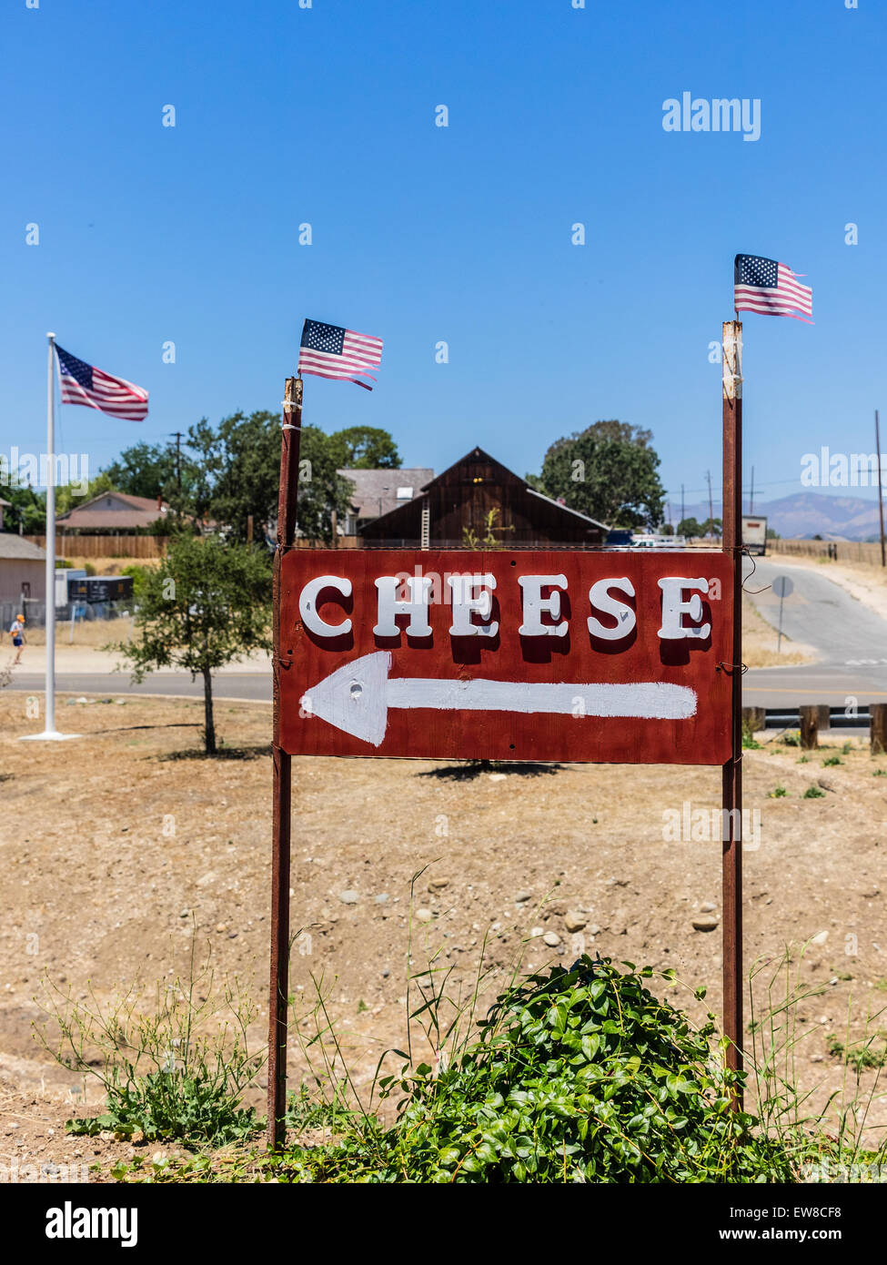 A cheese sign is topped with two American Flags while another flies in ...