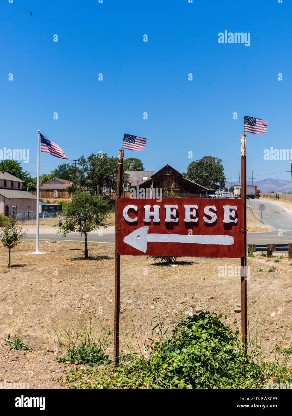 A cheese sign is topped with two American Flags while another flies in ...