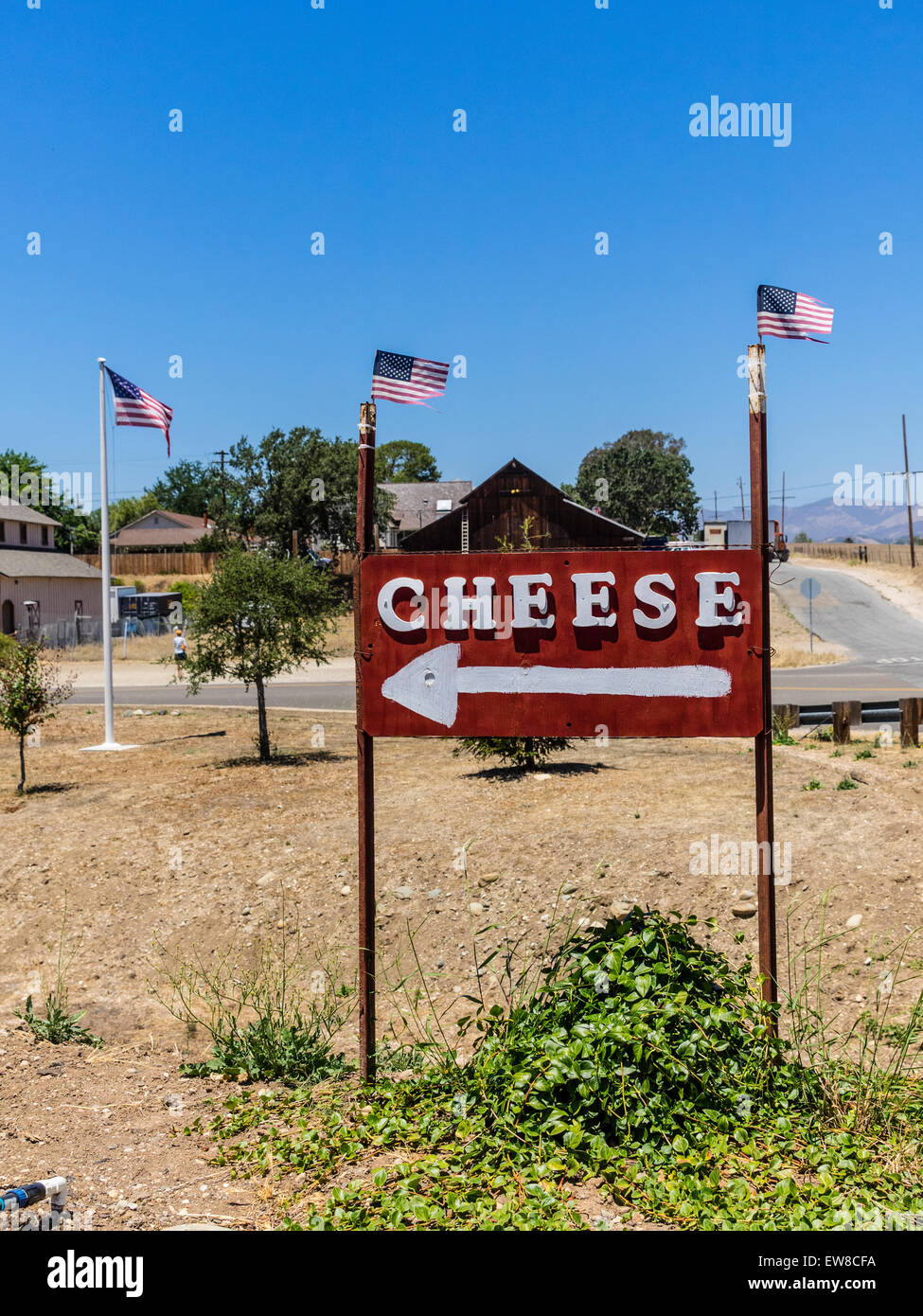 A cheese sign is topped with two American Flags while another flies in ...