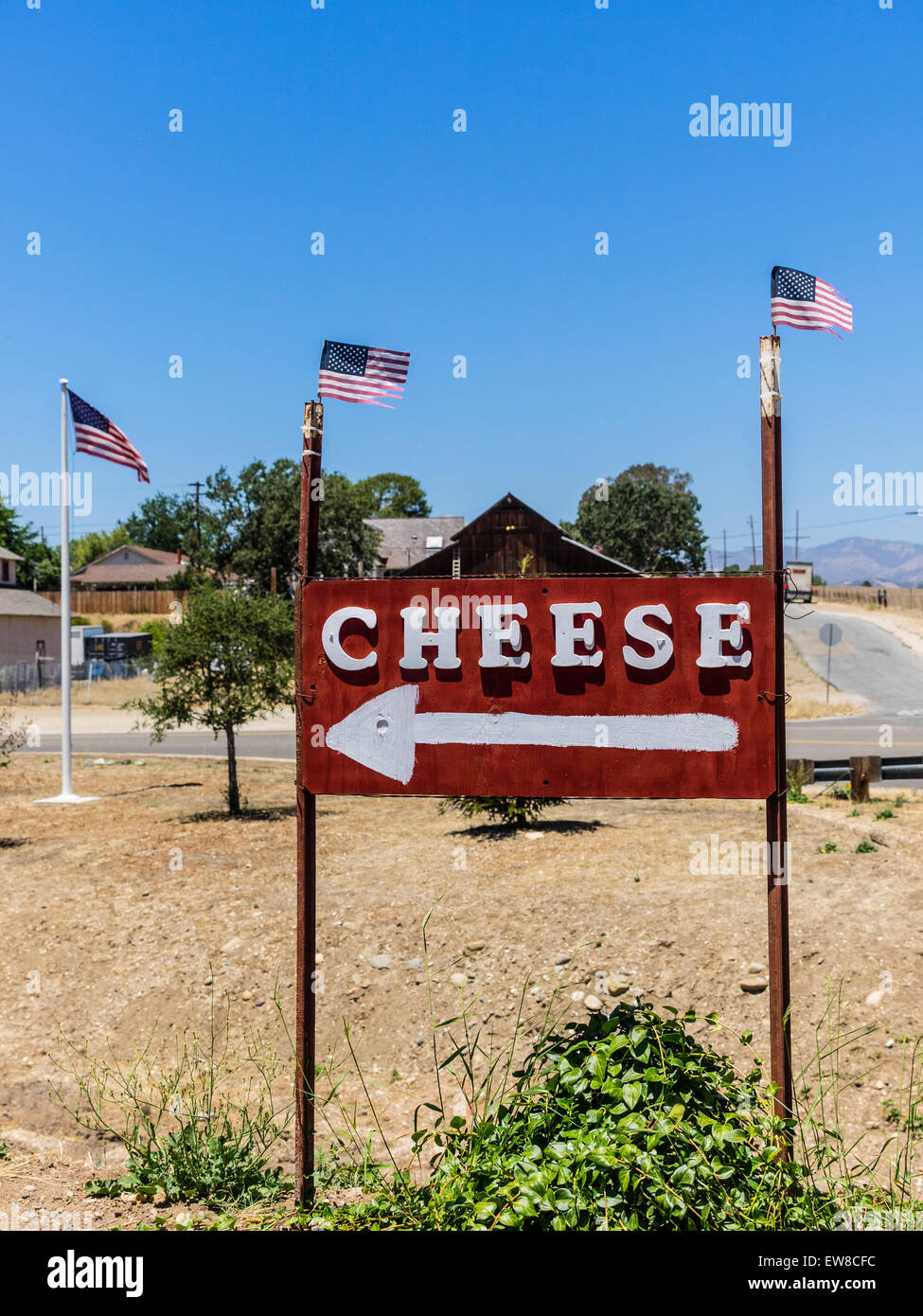 A cheese sign is topped with two American Flags while another flies in ...