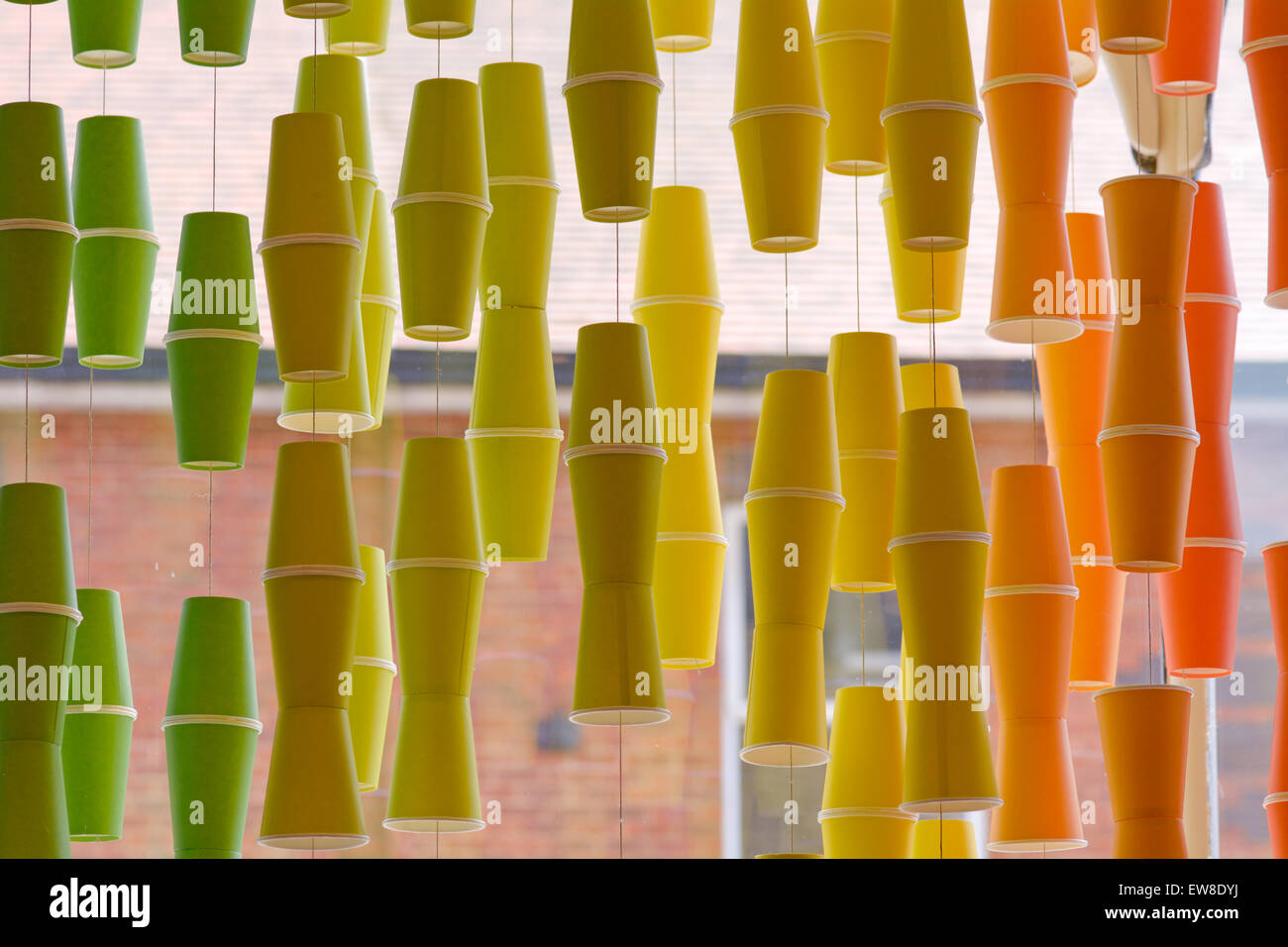 Color paper cups hanging in window display in shop Stock Photo - Alamy