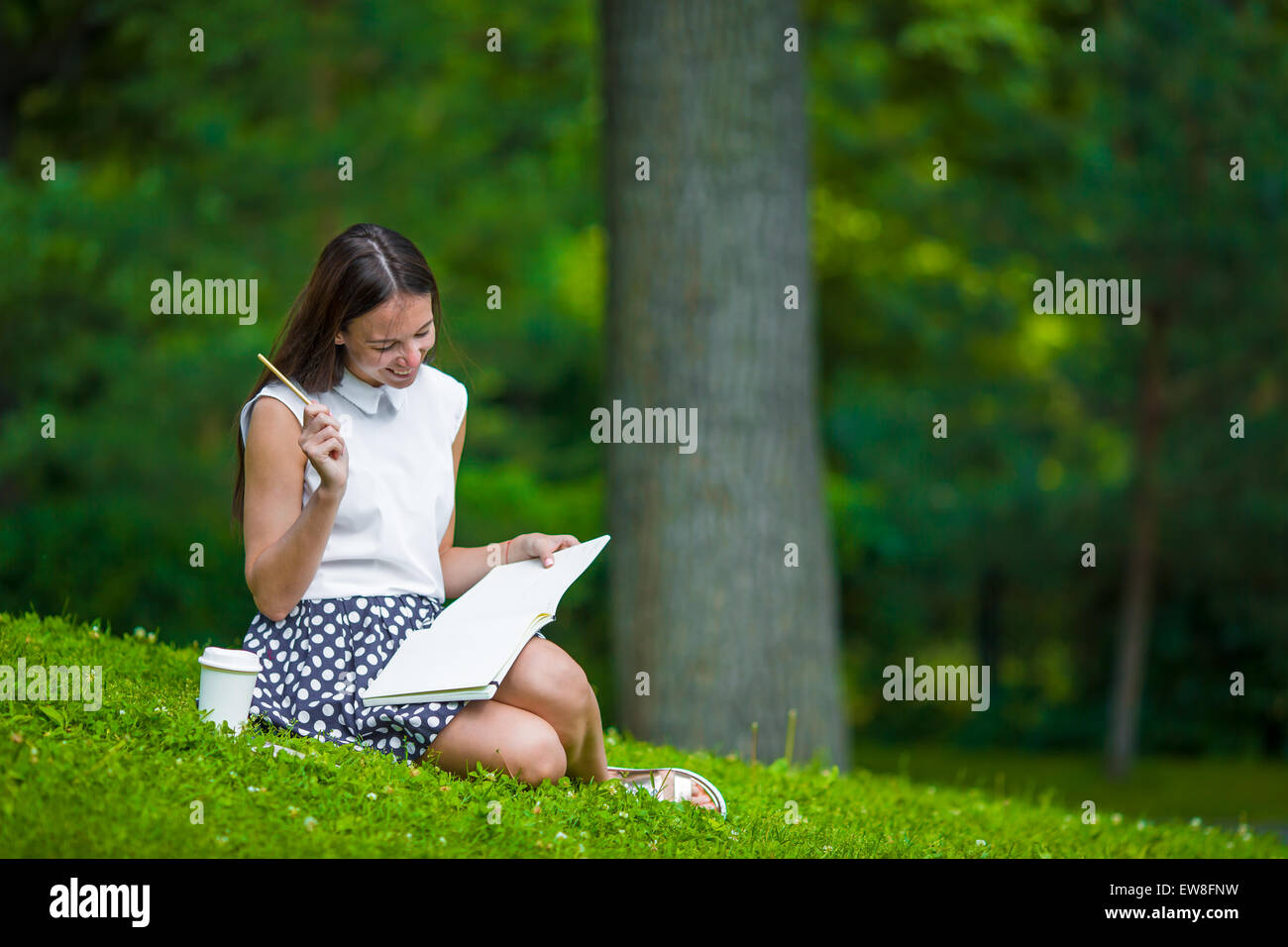 Young girl writing in her notebook outside at park Stock Photo - Alamy