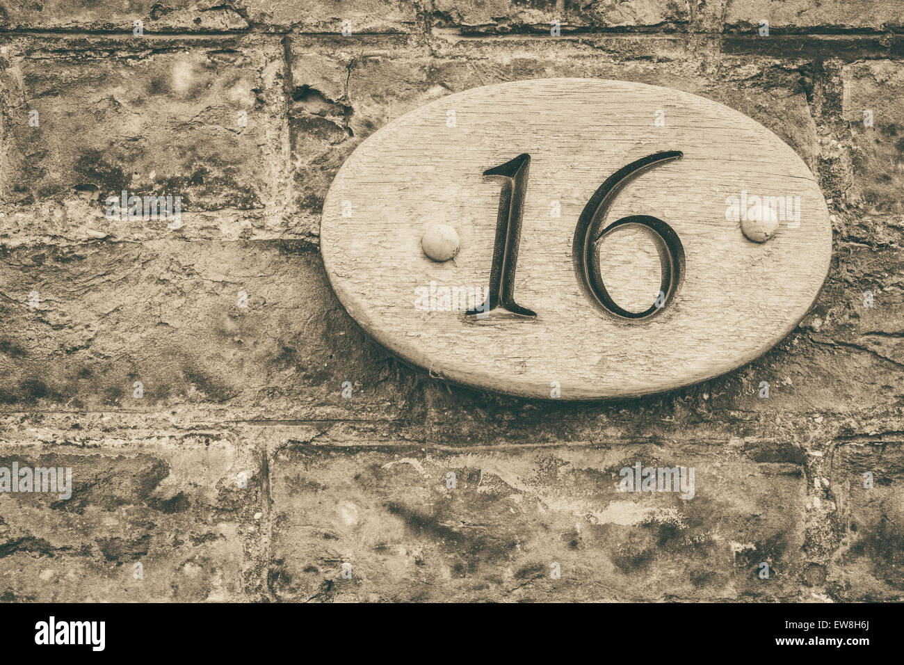 Wooden plate number 16 sixteen on brick wall conceptual image closeup ...