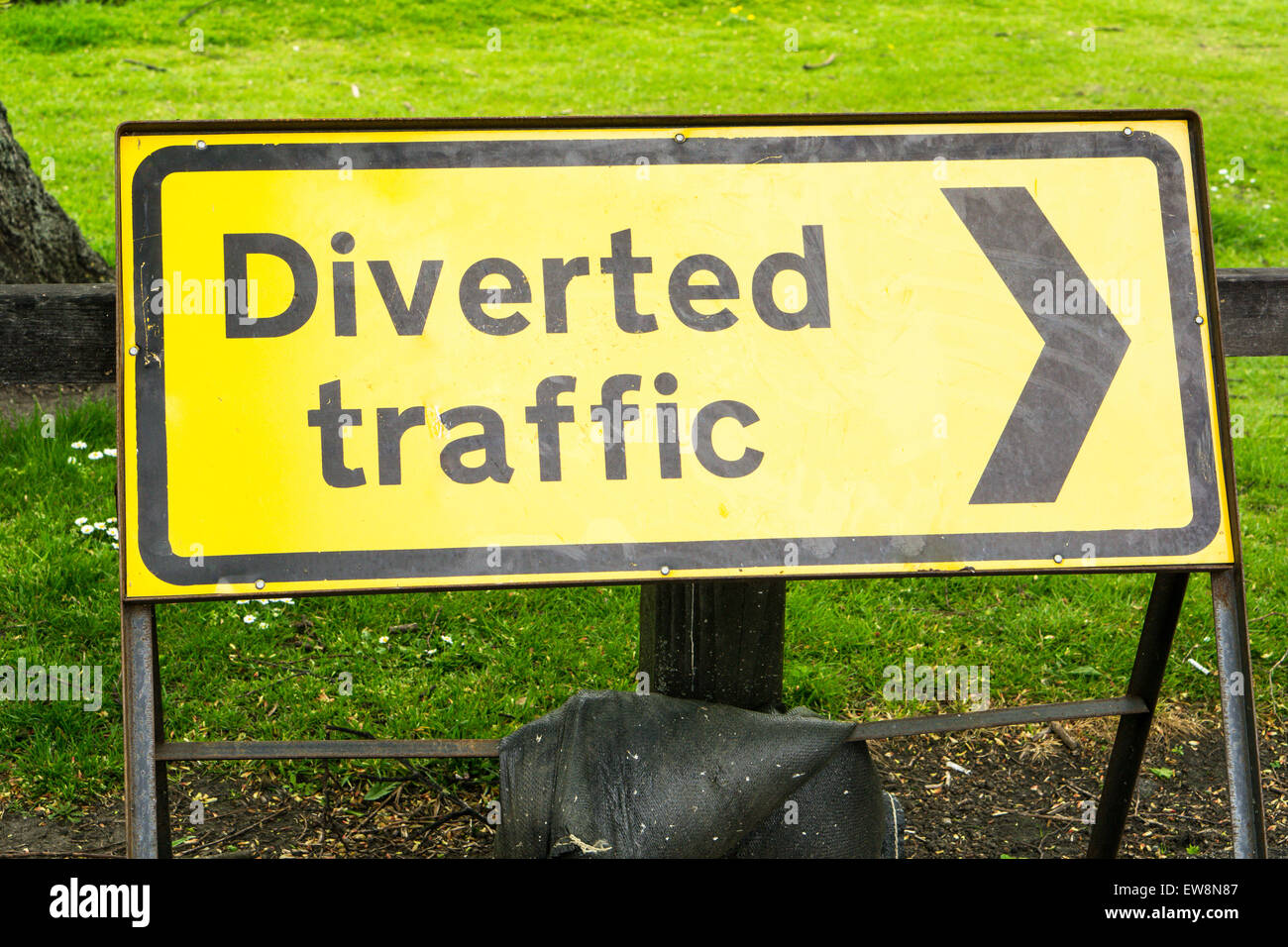 Sign for Diverted Traffic along a green path anchored by a sand bag ...