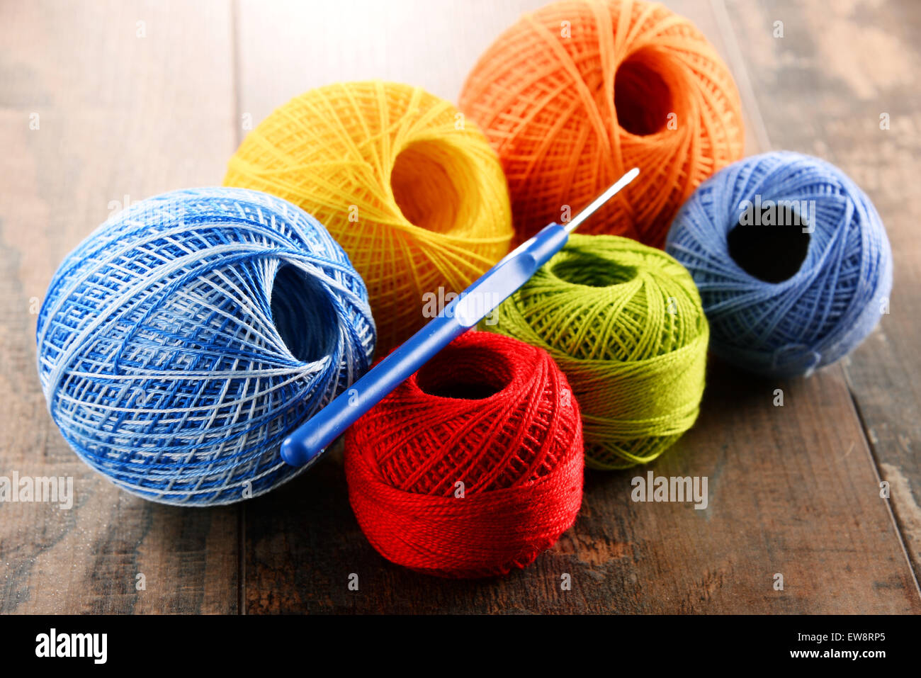 Colorful yarn for crocheting and hook on wooden table Stock Photo - Alamy