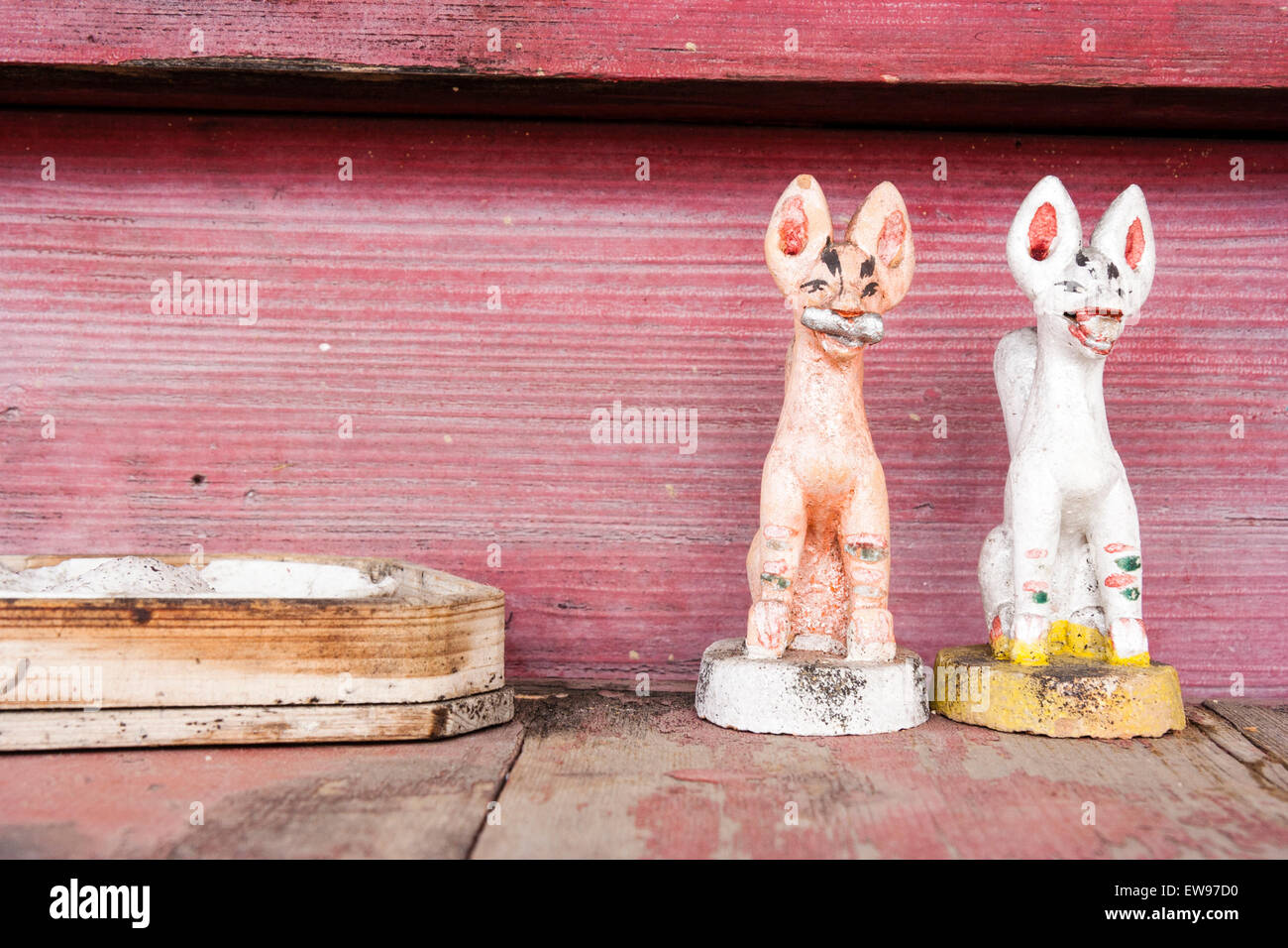 Two small painted Inari, fox, ceramic statues placed in front of pink ...