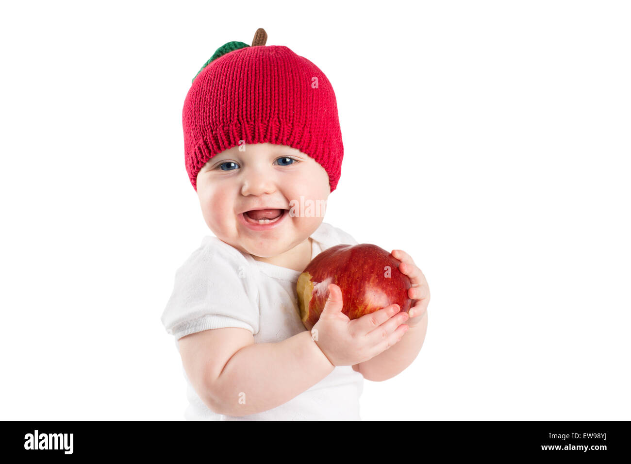 Cute little baby in a knitted apple hat biting in a red ripe apple ...