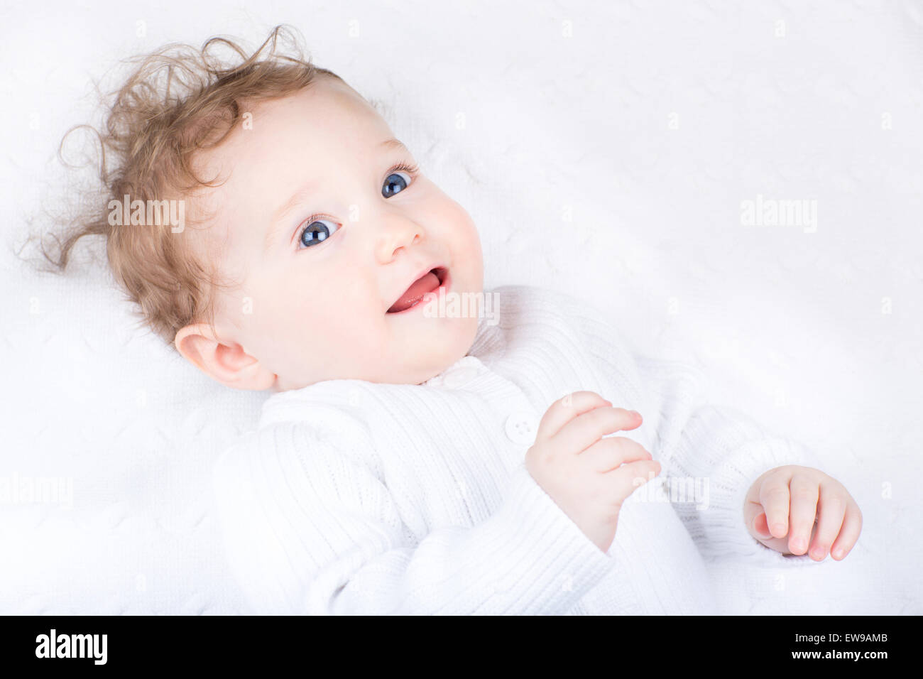 Beautiful curly baby on a white blanket Stock Photo - Alamy