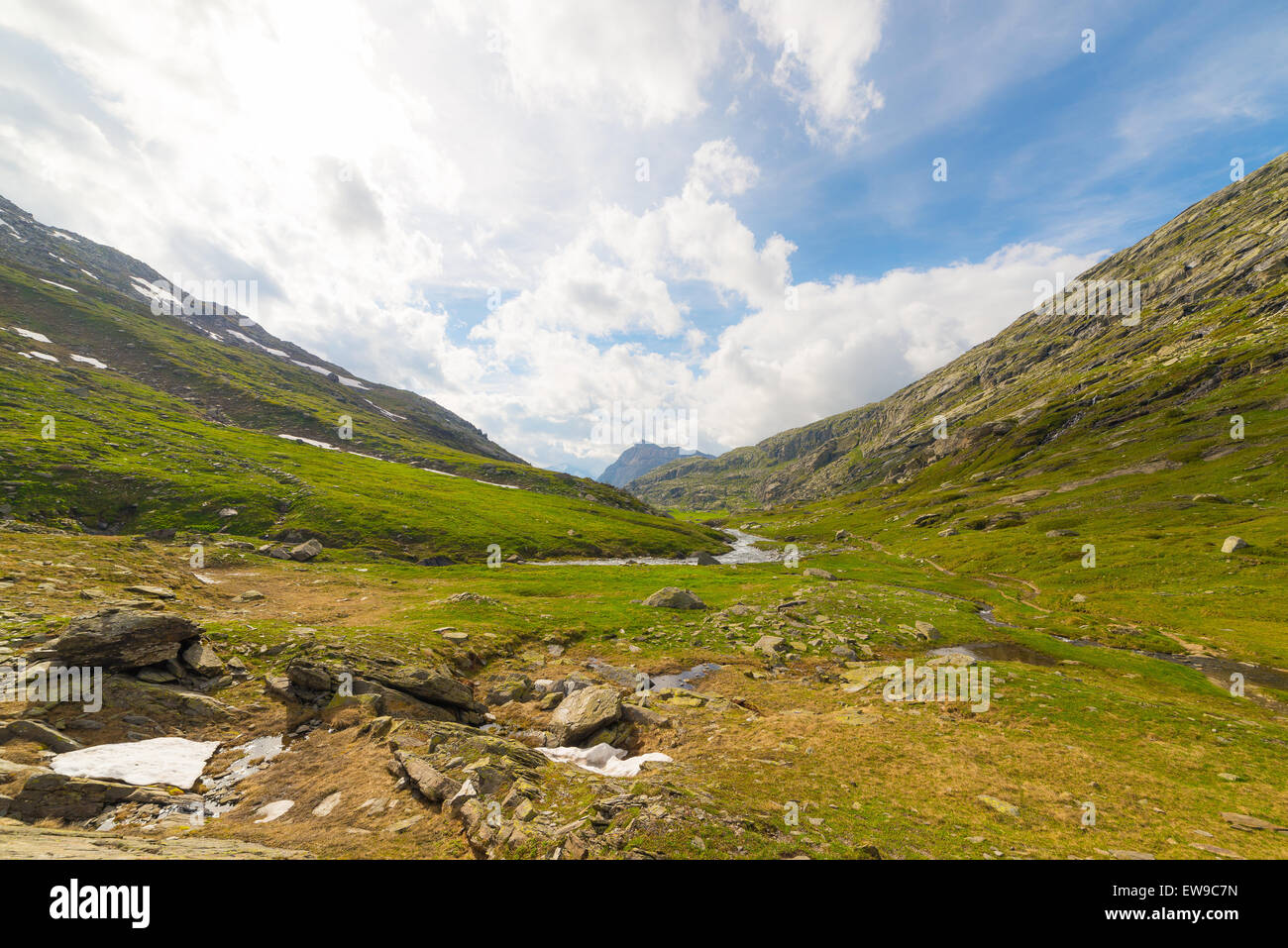 Alpine stream flowing down at the bottom of huge valley, remaining ...