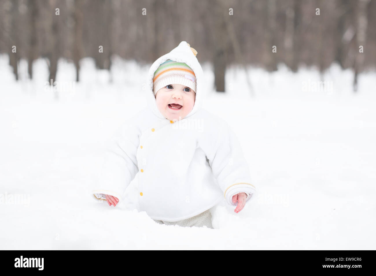 Little funny baby digging in the snow Stock Photo - Alamy