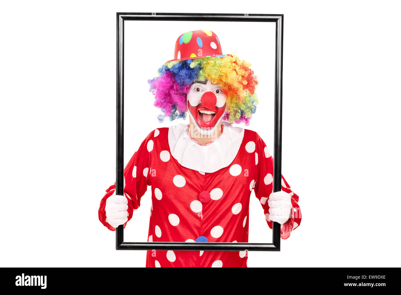 Male clown holding a big picture frame and posing behind it isolated on ...