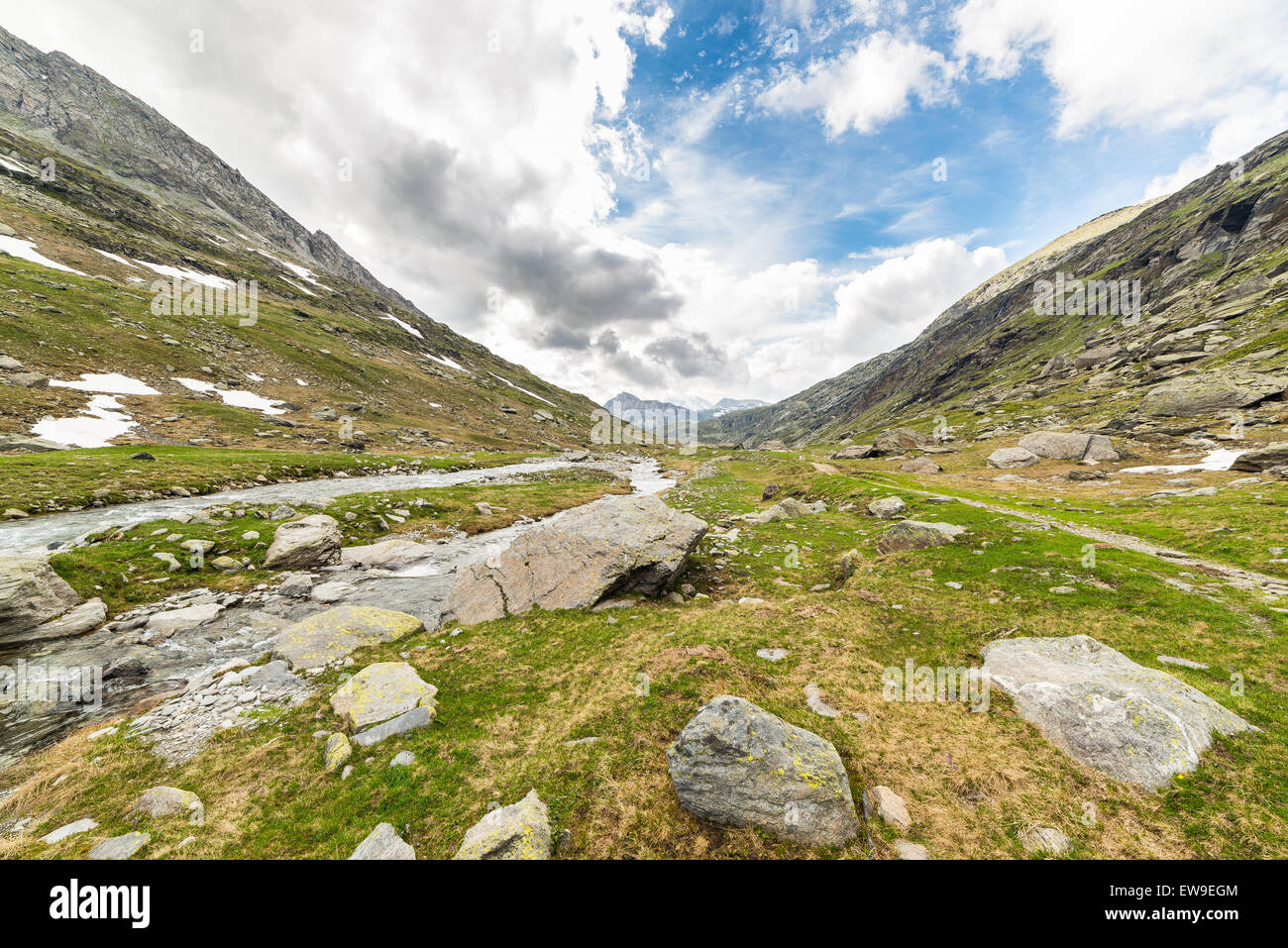 Alpine stream flowing down at the bottom of huge valley, remaining ...